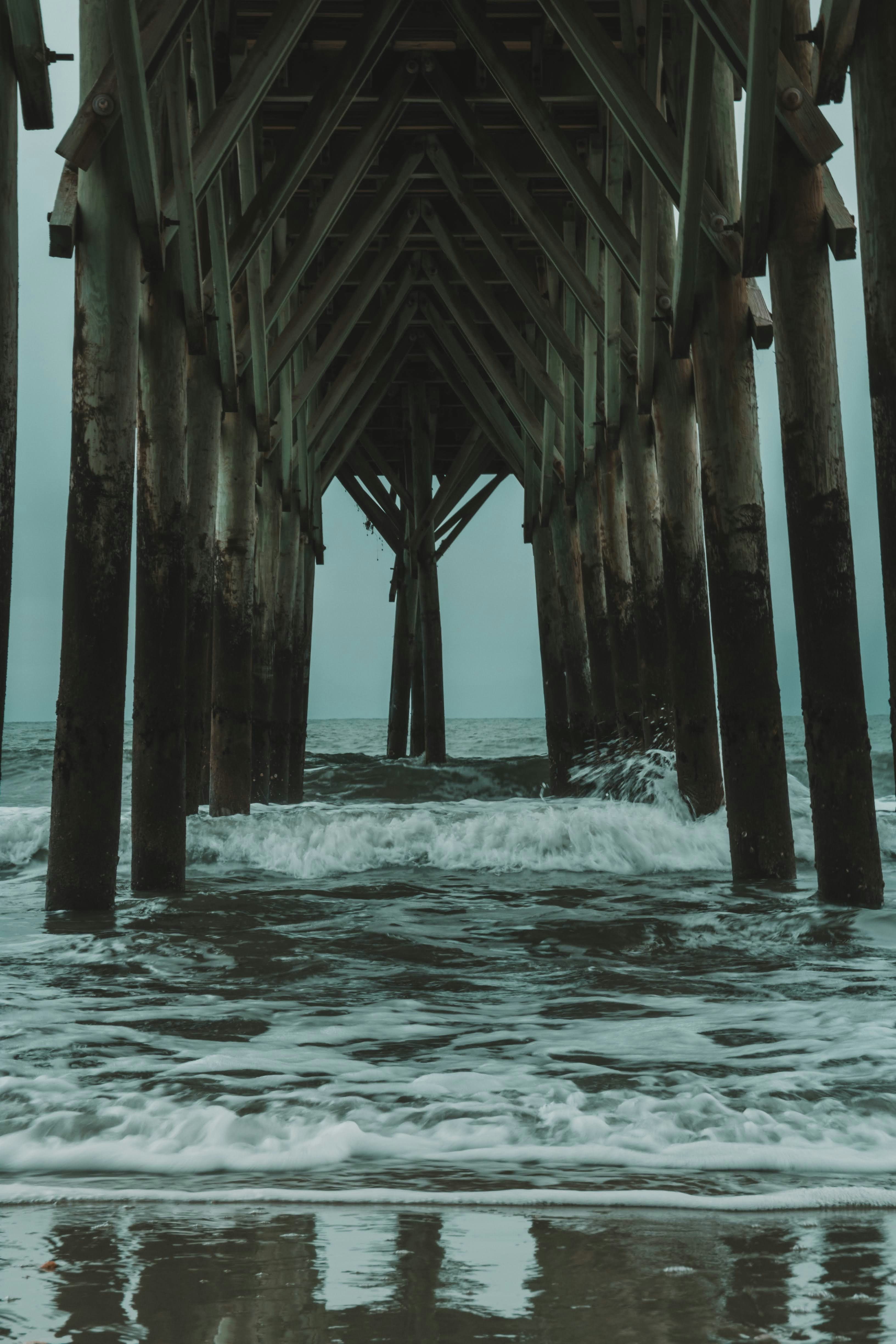 The underside of a pier with waves coming in photo – Free Water Image ...