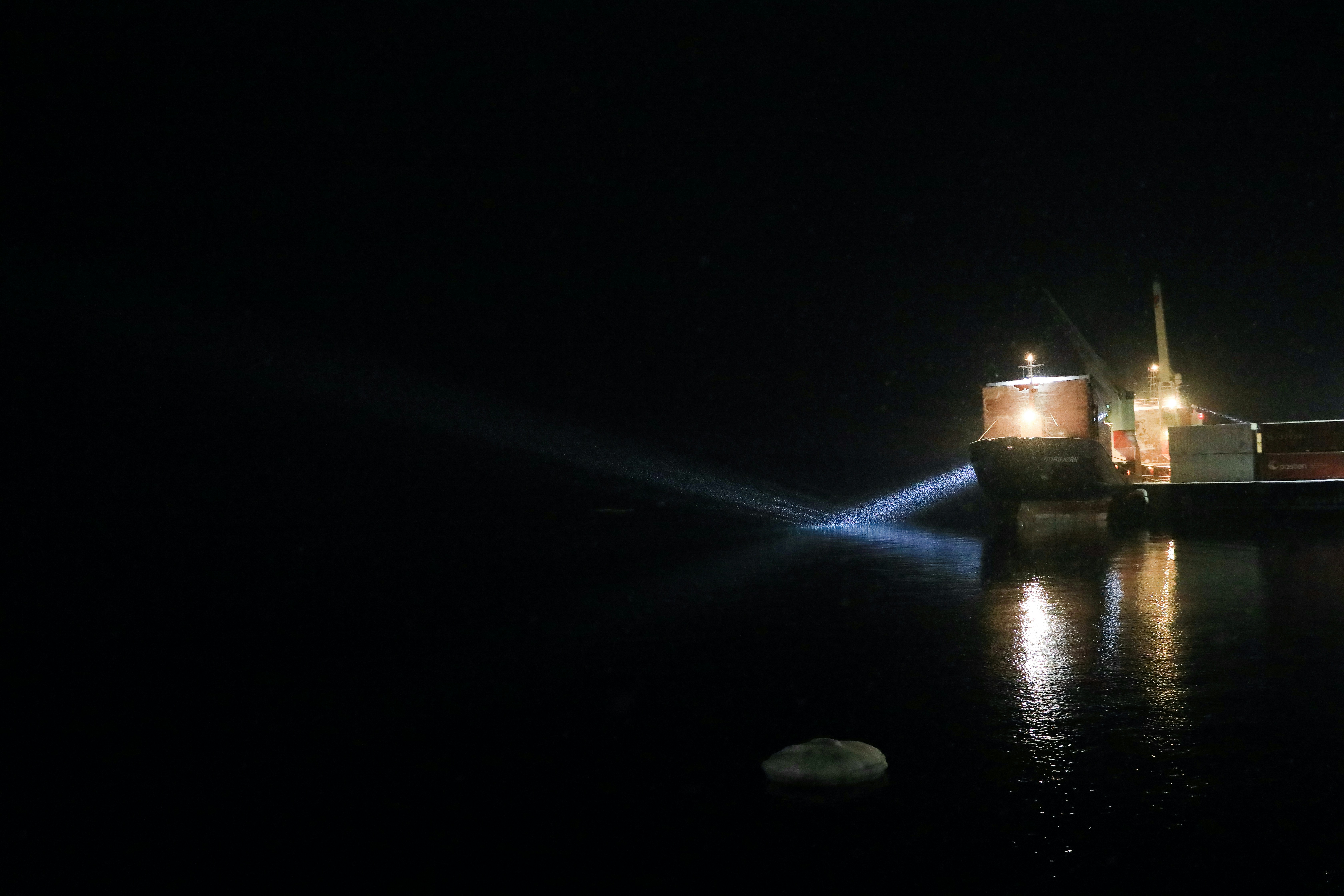 Night Beacon: A Lone Vessel Pierces Darkness with a Diagonal Searchlight