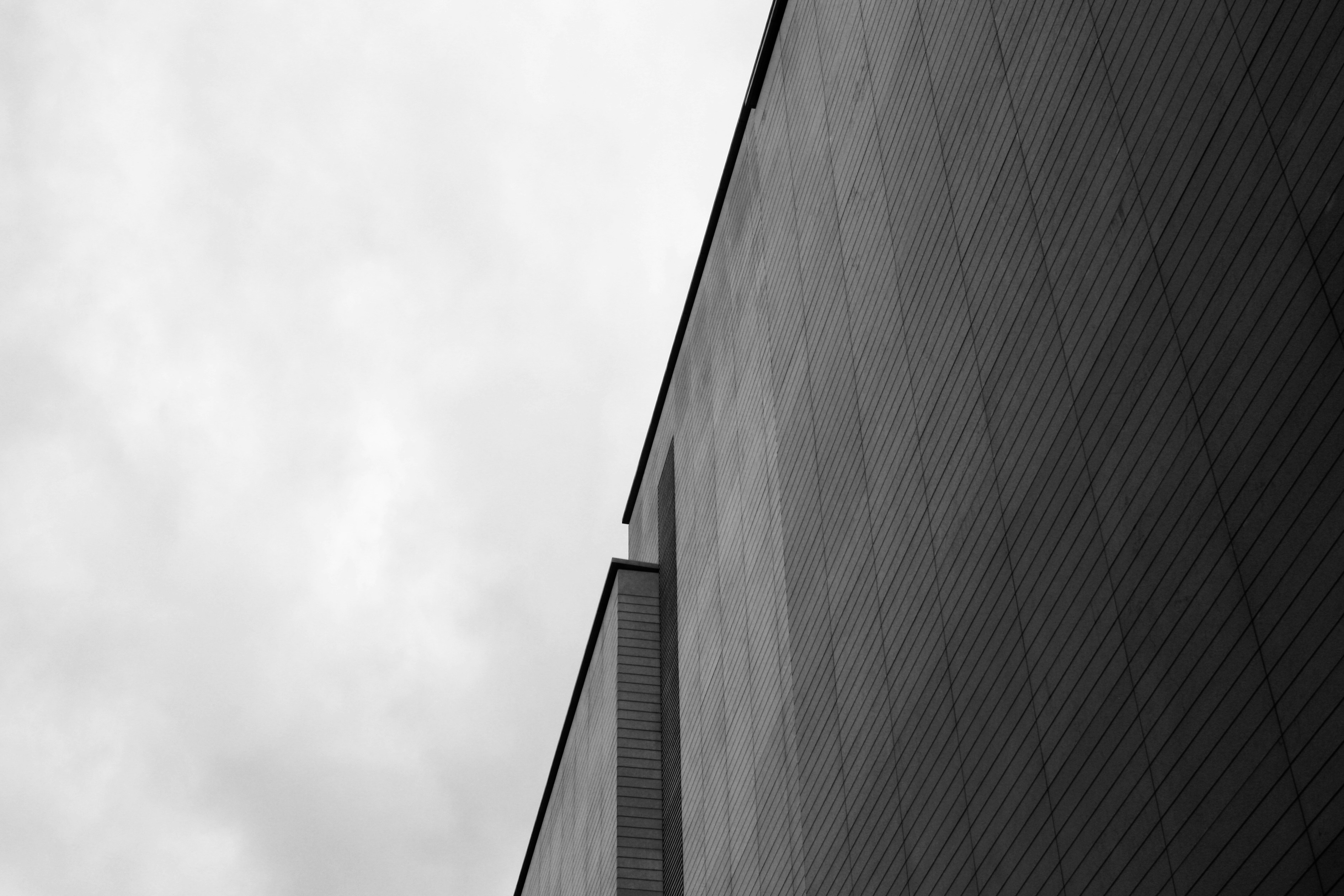 Angular view of a modern building's facade, showcasing its textured surface against a cloudy sky.