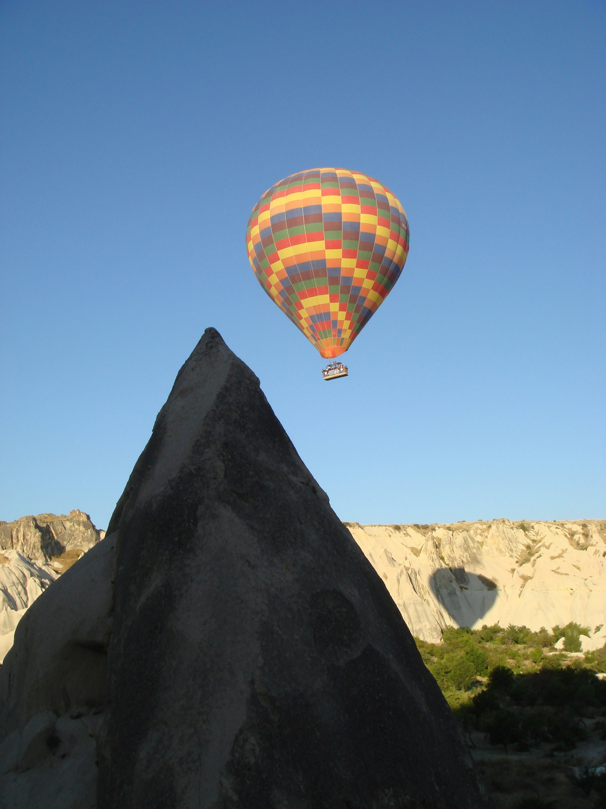 A hot air balloon flying over a large rock photo – Free Blue Image on ...