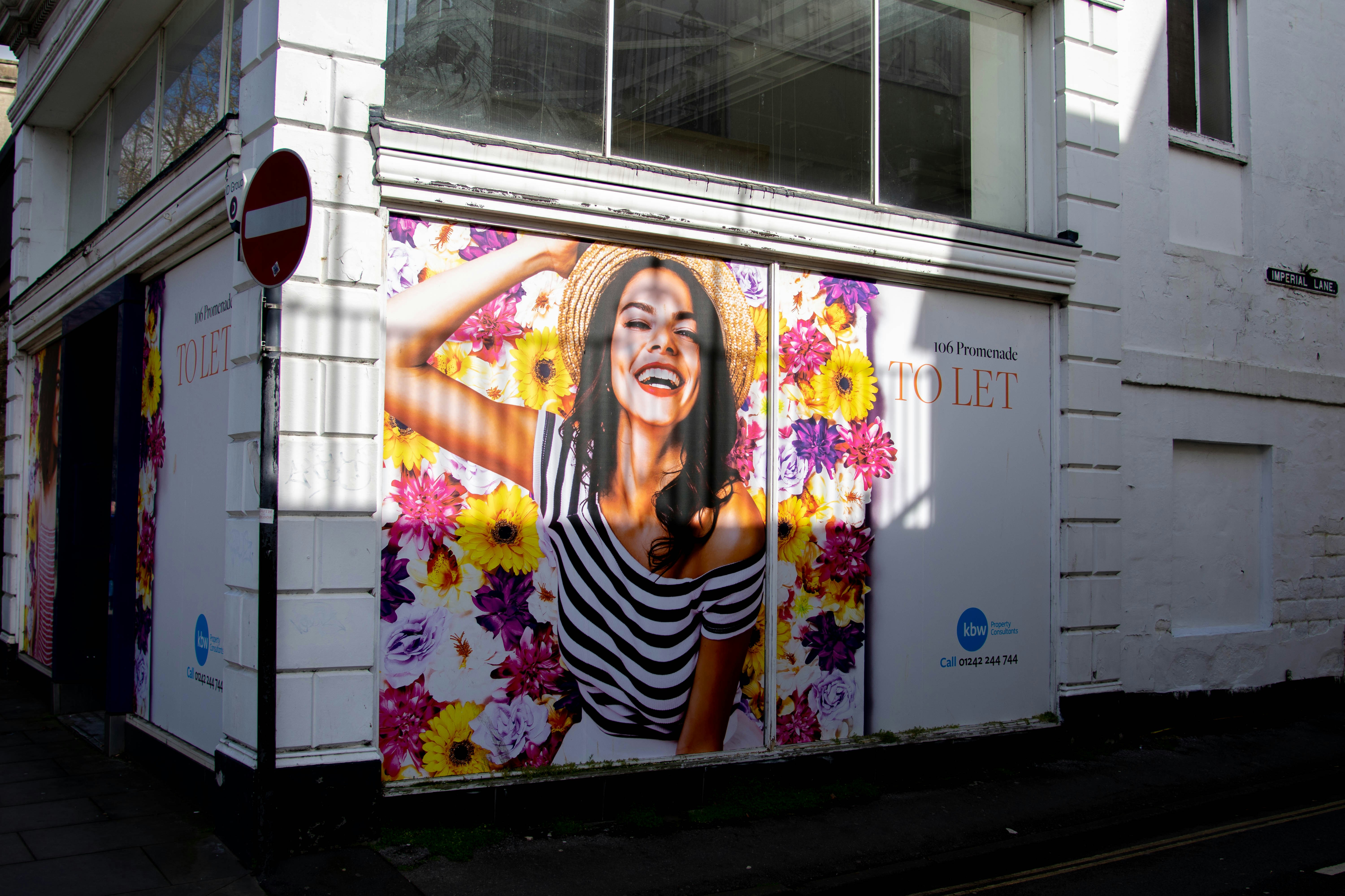 A colorful advertisement featuring a woman smiling amidst a backdrop of vibrant flowers, promoting a property for rent. The design blends natural beauty with a cheerful message.