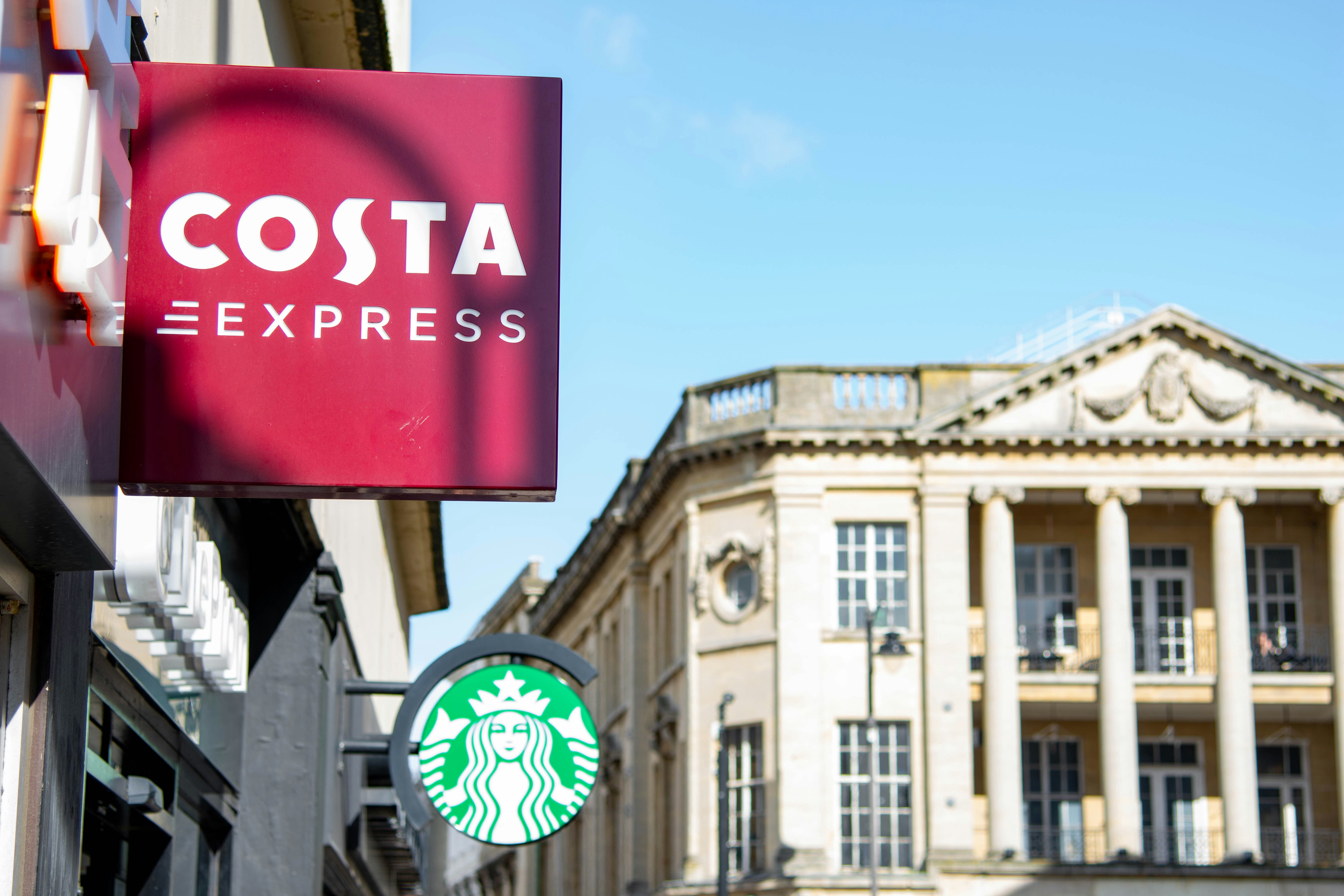 A starbucks sign hanging from the side of a building photo – Free ...