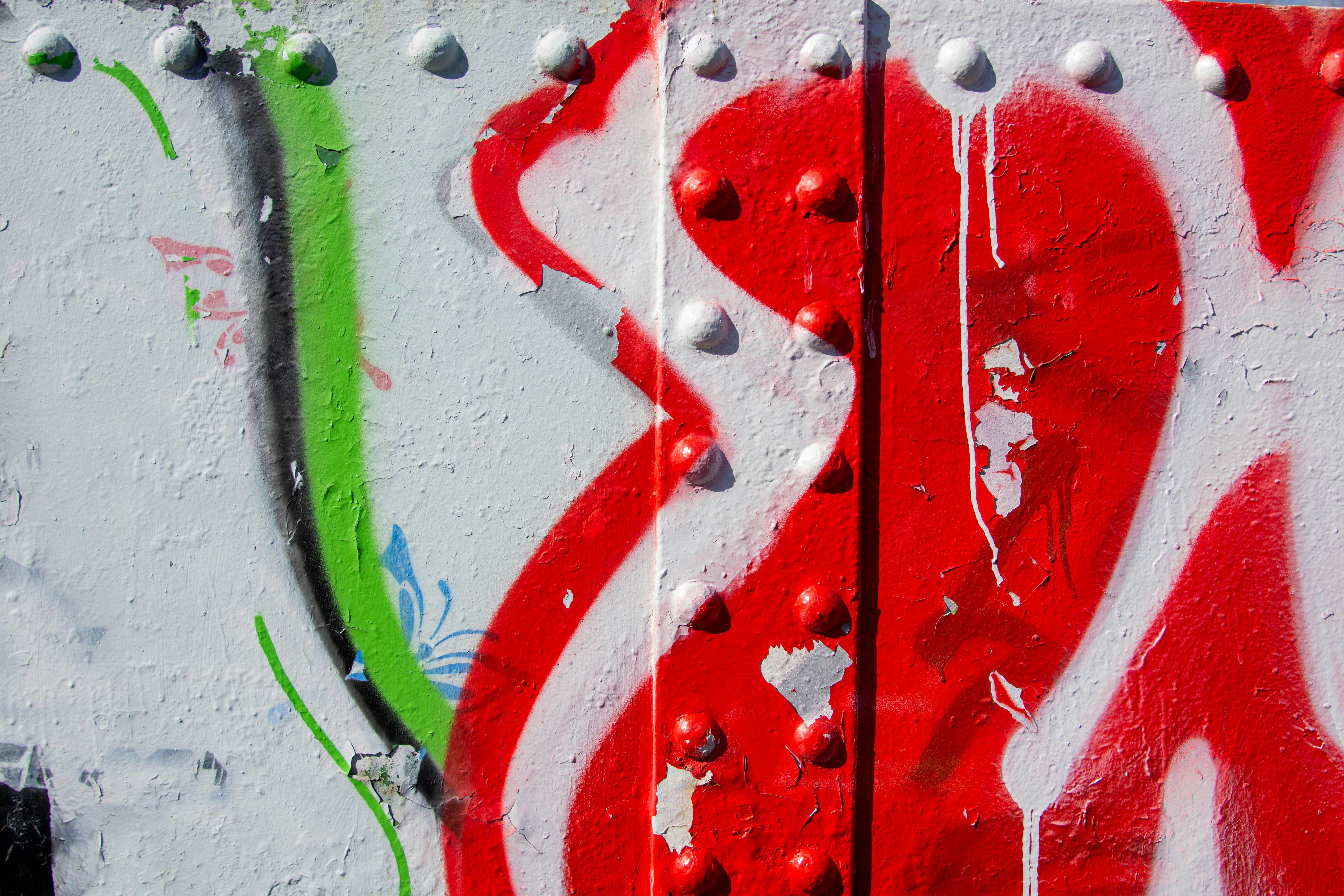 Split-Panel Graffiti: Red Curves Across Riveted Metal