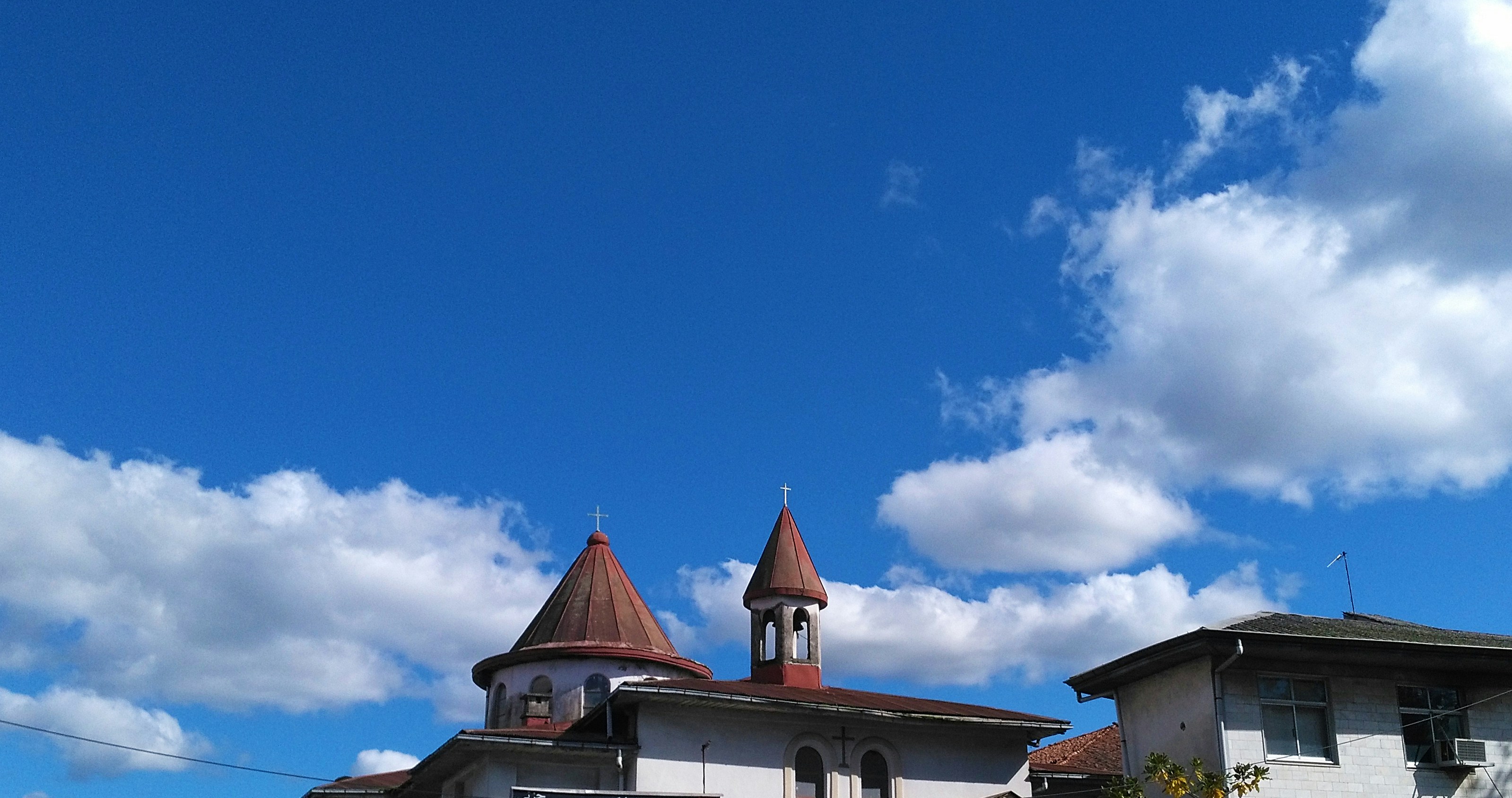 White building with twin towers under a vivid blue sky with scattered clouds.