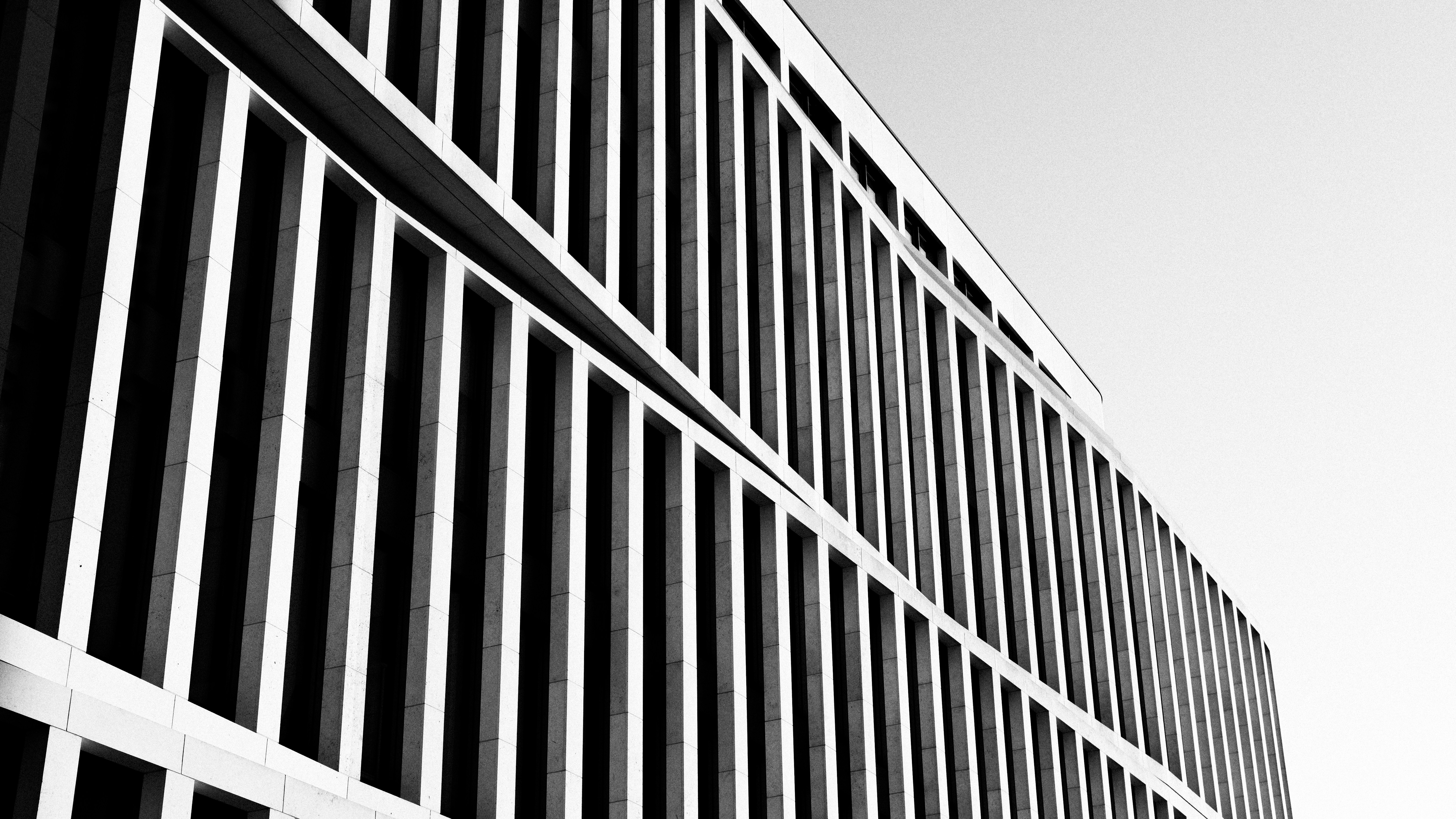 Abstract view of a contemporary building's facade showcasing its rhythmic lines and patterns in black and white.
