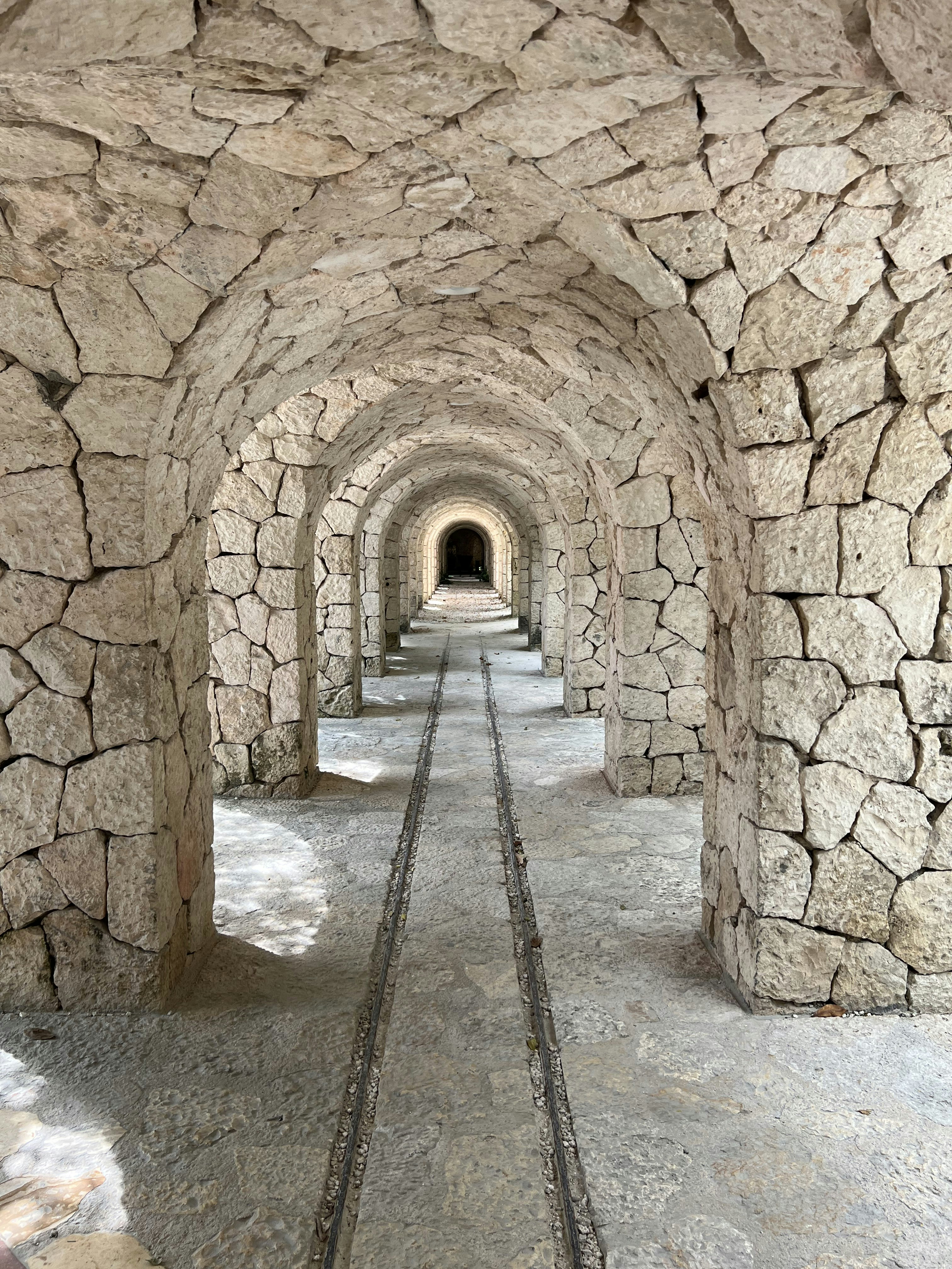 Stone tunnel with a train track running through a series of archways.