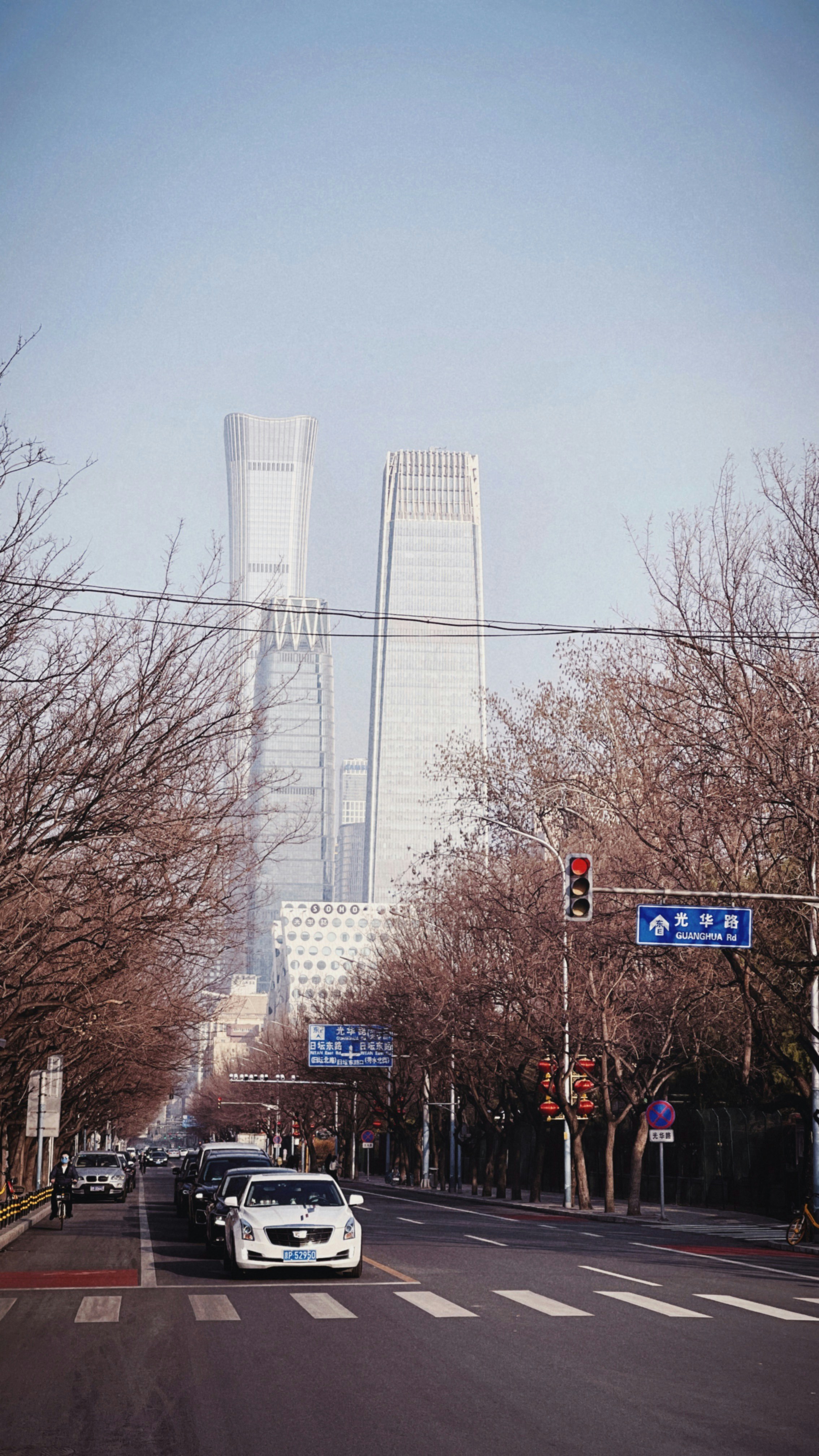 a white car driving down a street next to tall buildings