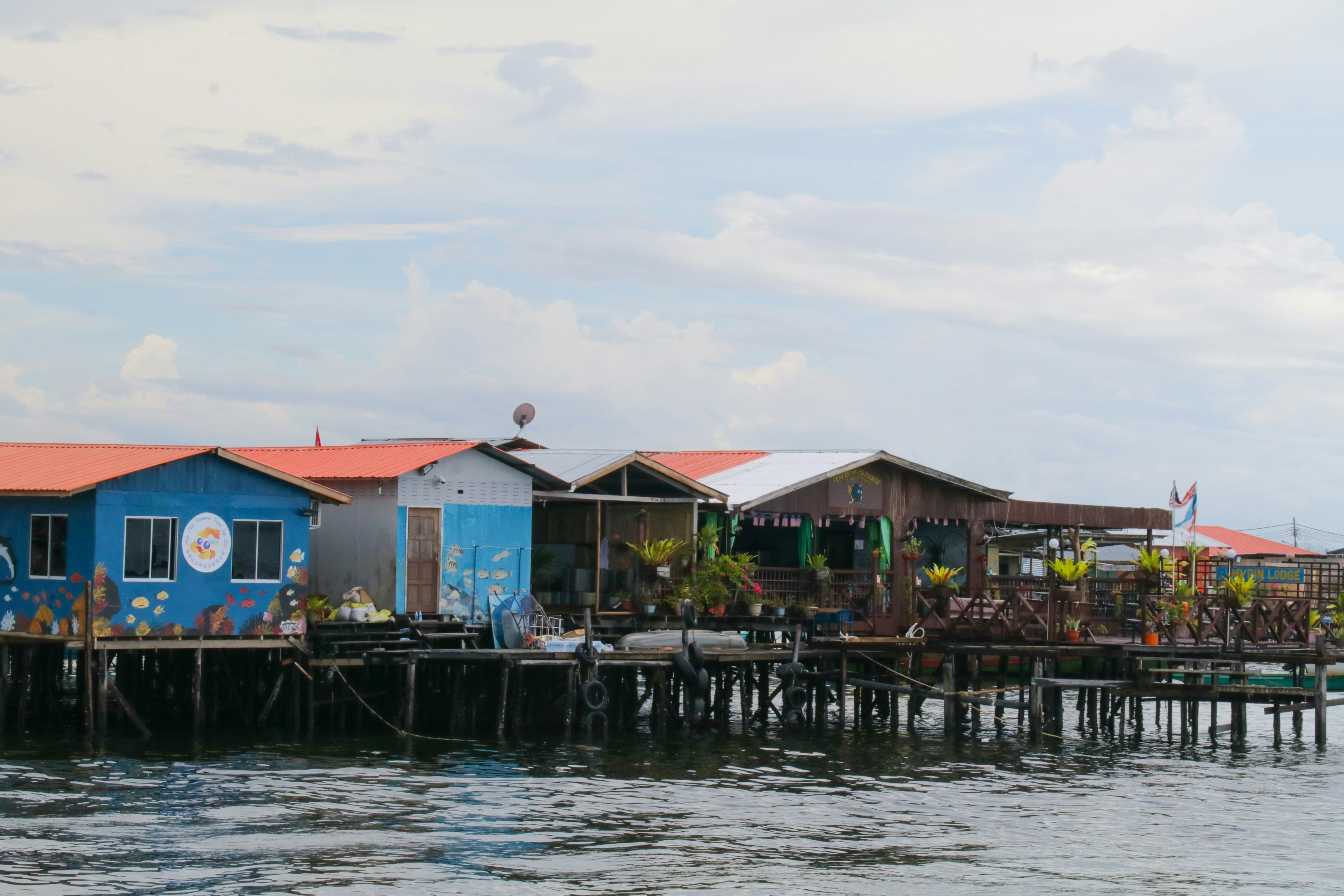 Colorful stilt houses line the water's edge, showcasing local architecture and community life. The scene captures a blend of nature and human habitation.