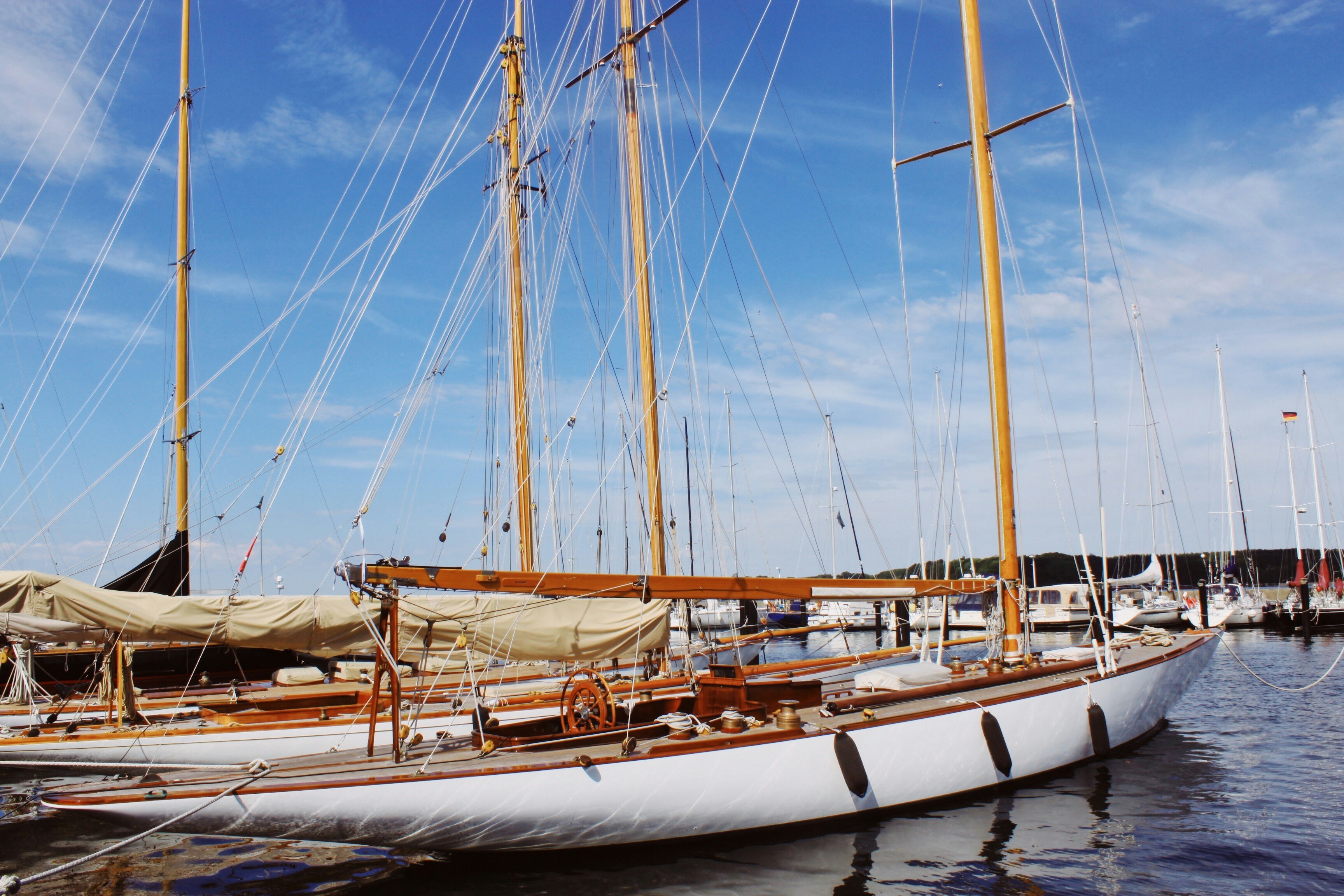 Elegant sailboat docked among other vessels under a clear blue sky.
