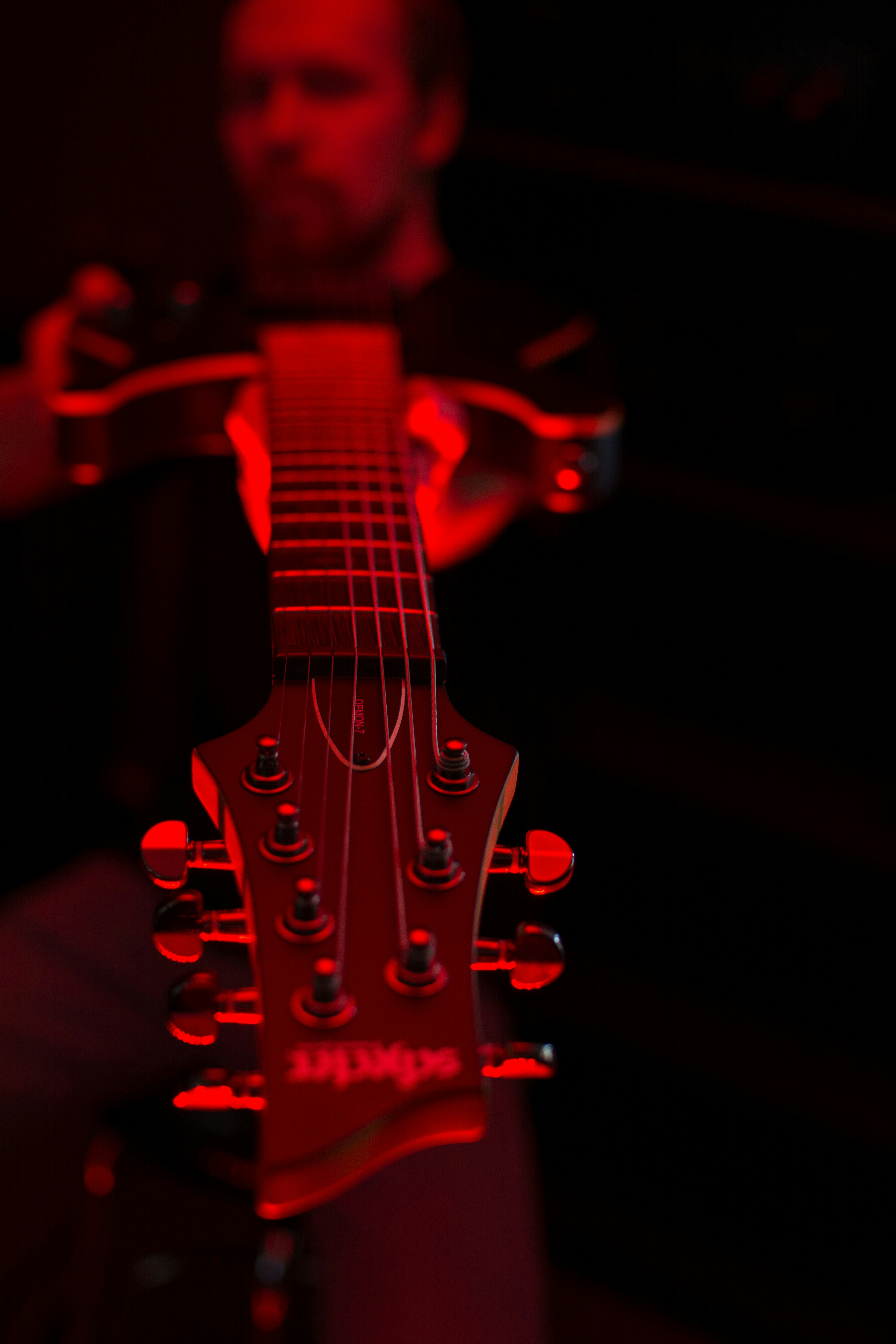 Crimson Crown: Close-Up Guitar Headstock in Stage Light