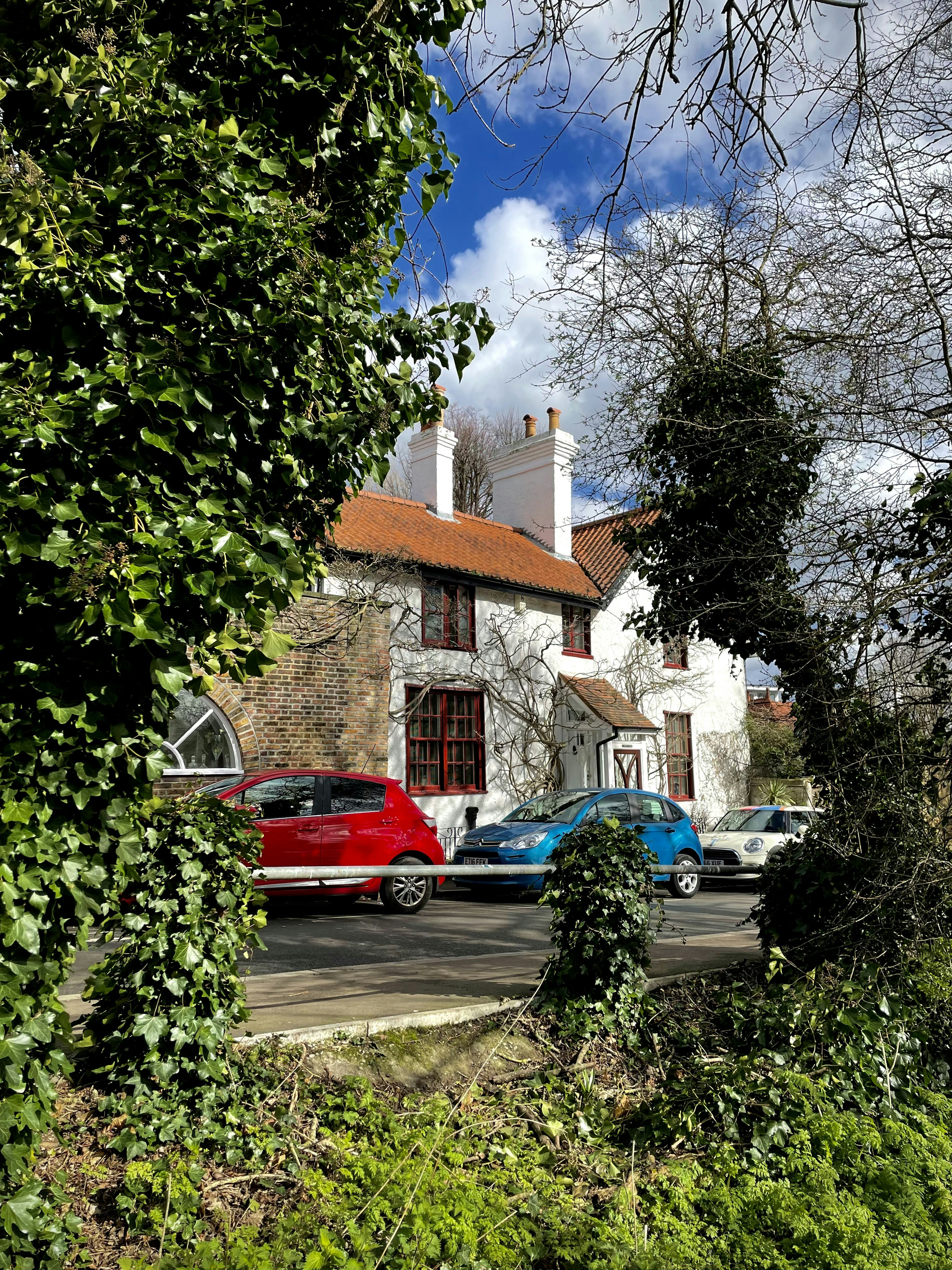 Blue Hatchback Framed by Ivy-Cloaked Arches on a Quiet English Street