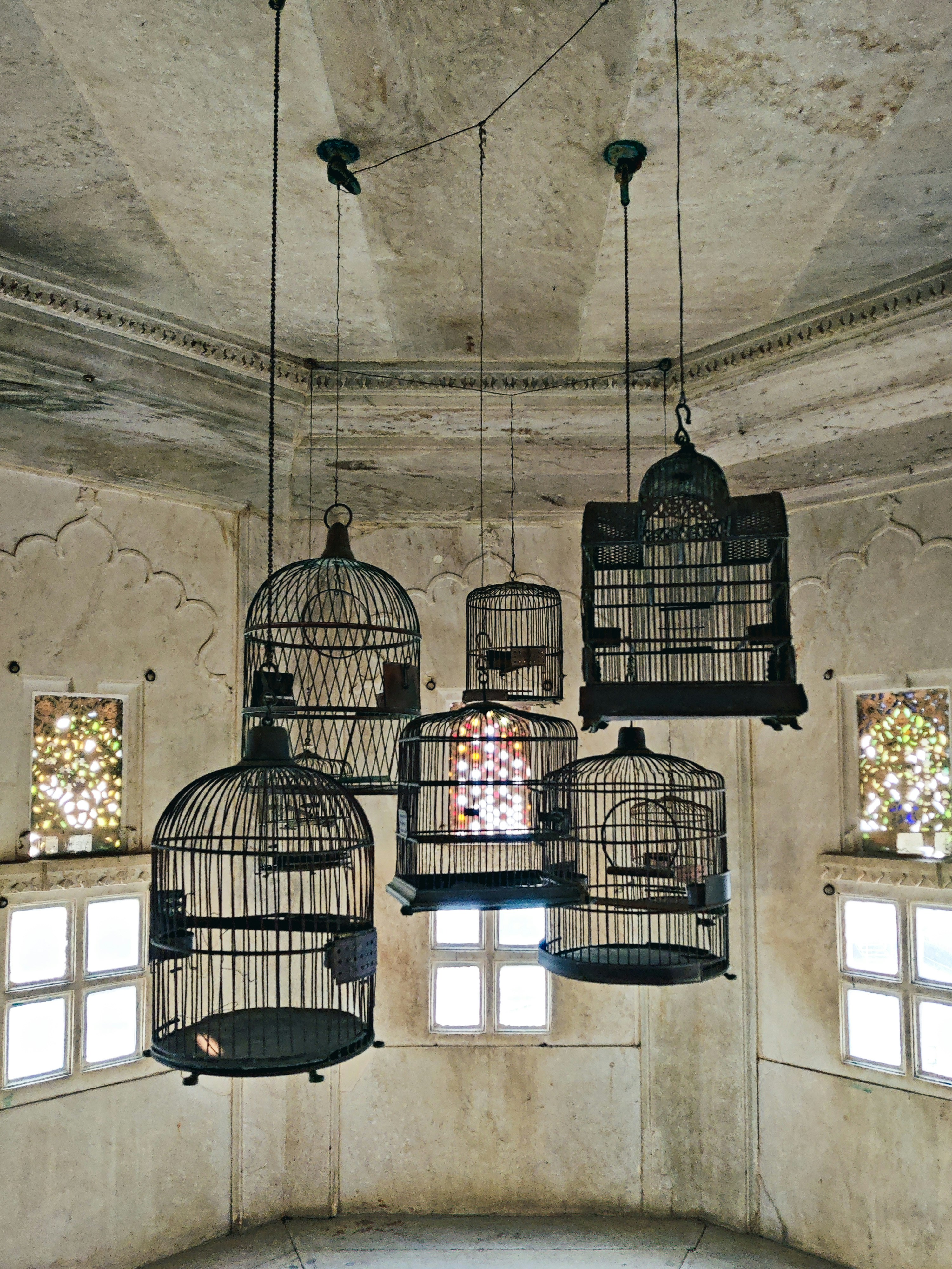 a bunch of bird cages hanging from a ceiling