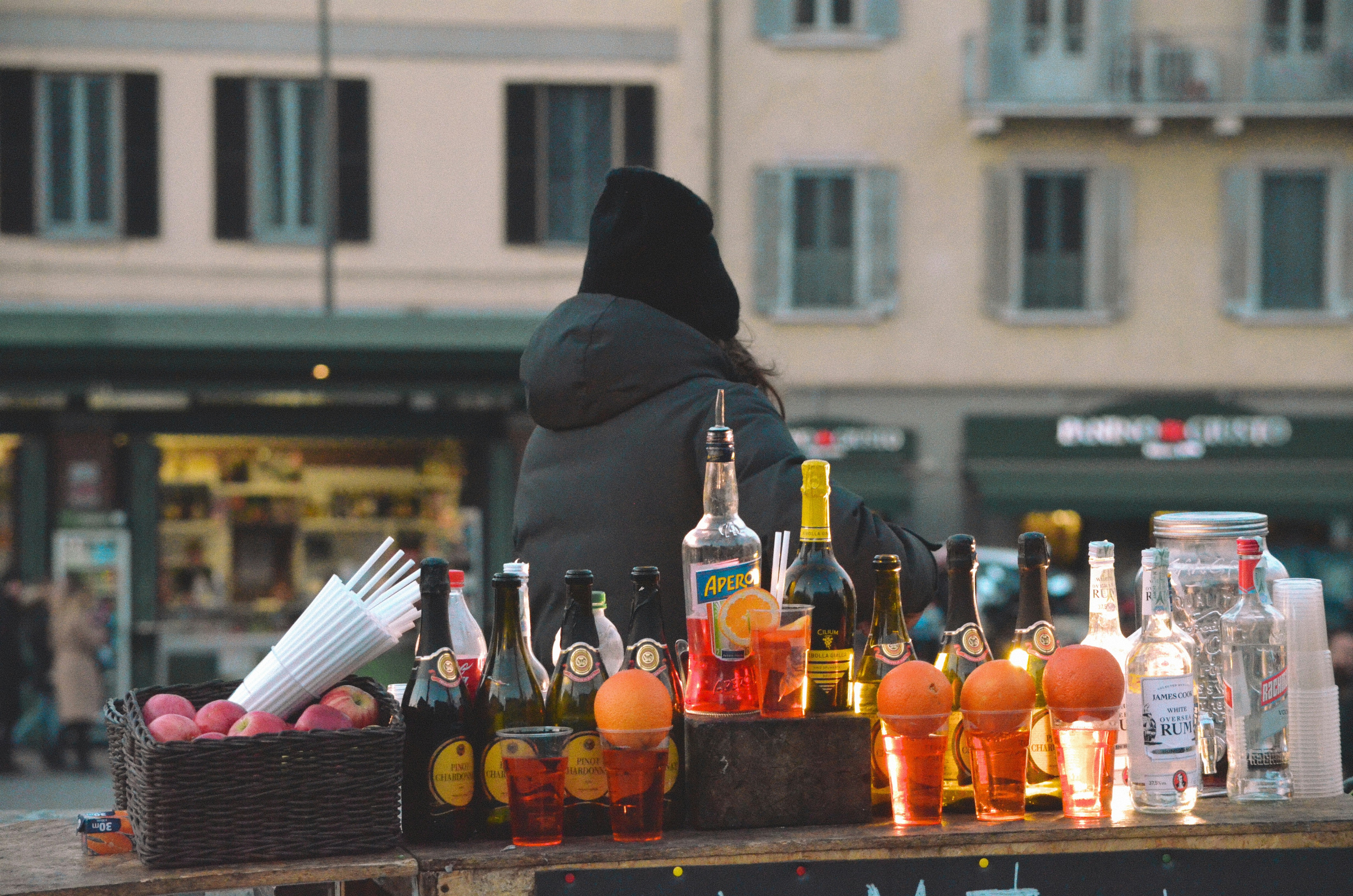 Evening Bar Scene: A Quiet Counter with Bottles and a Lone Figure in the Background