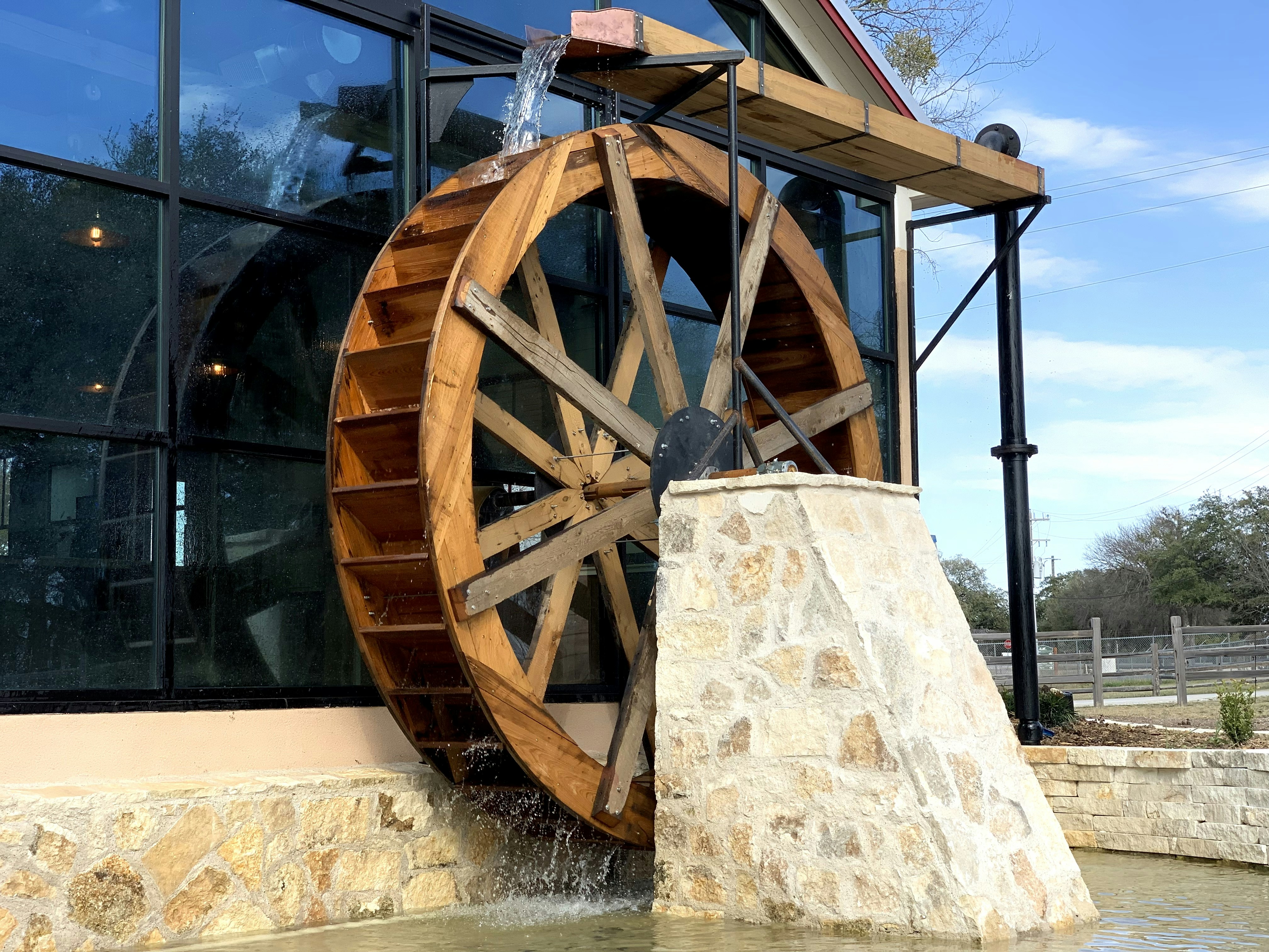 A large water wheel in front of a building photo – Free Wood Image on ...