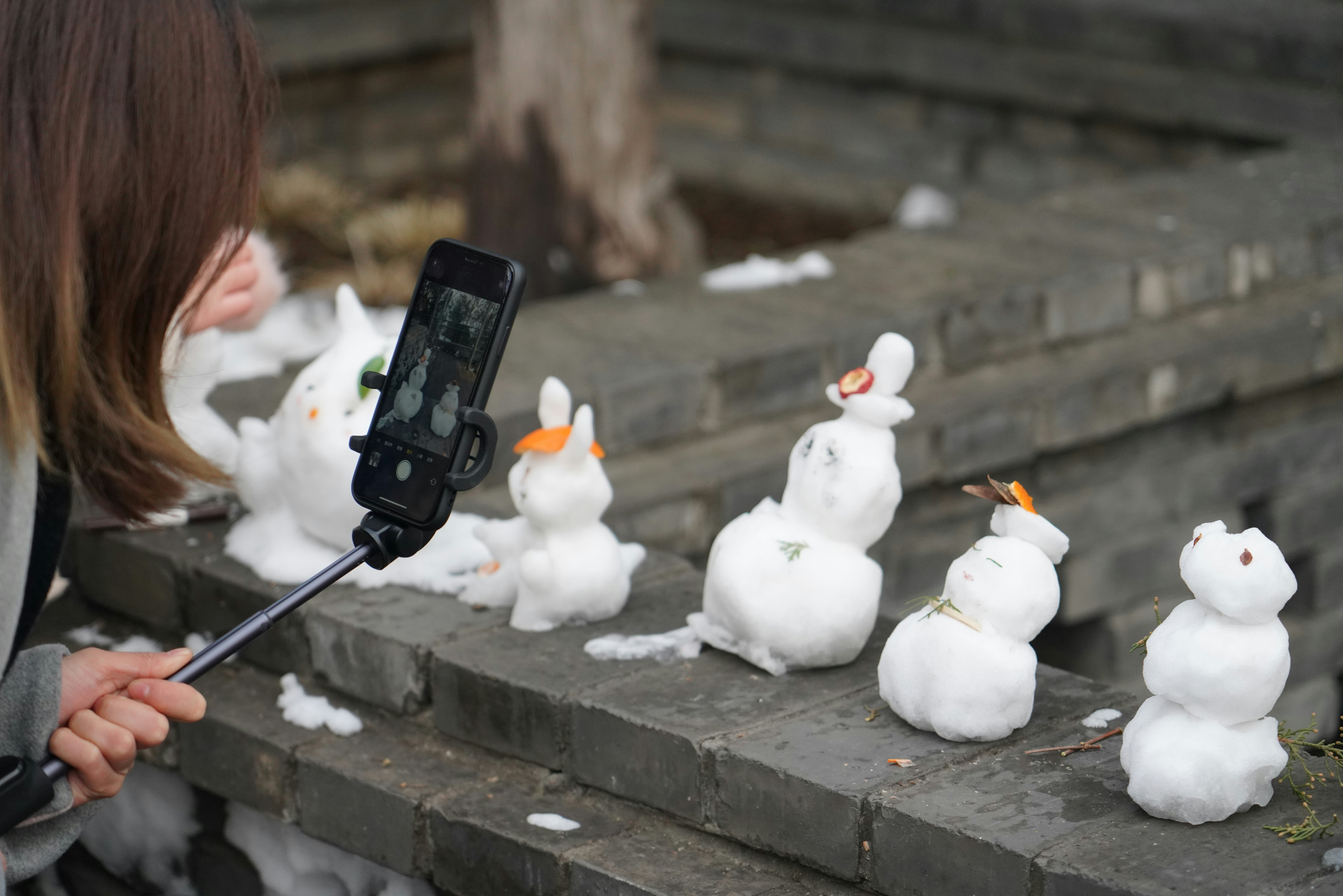A woman taking a picture of a bunch of snowmen photo – Free Beijing ...