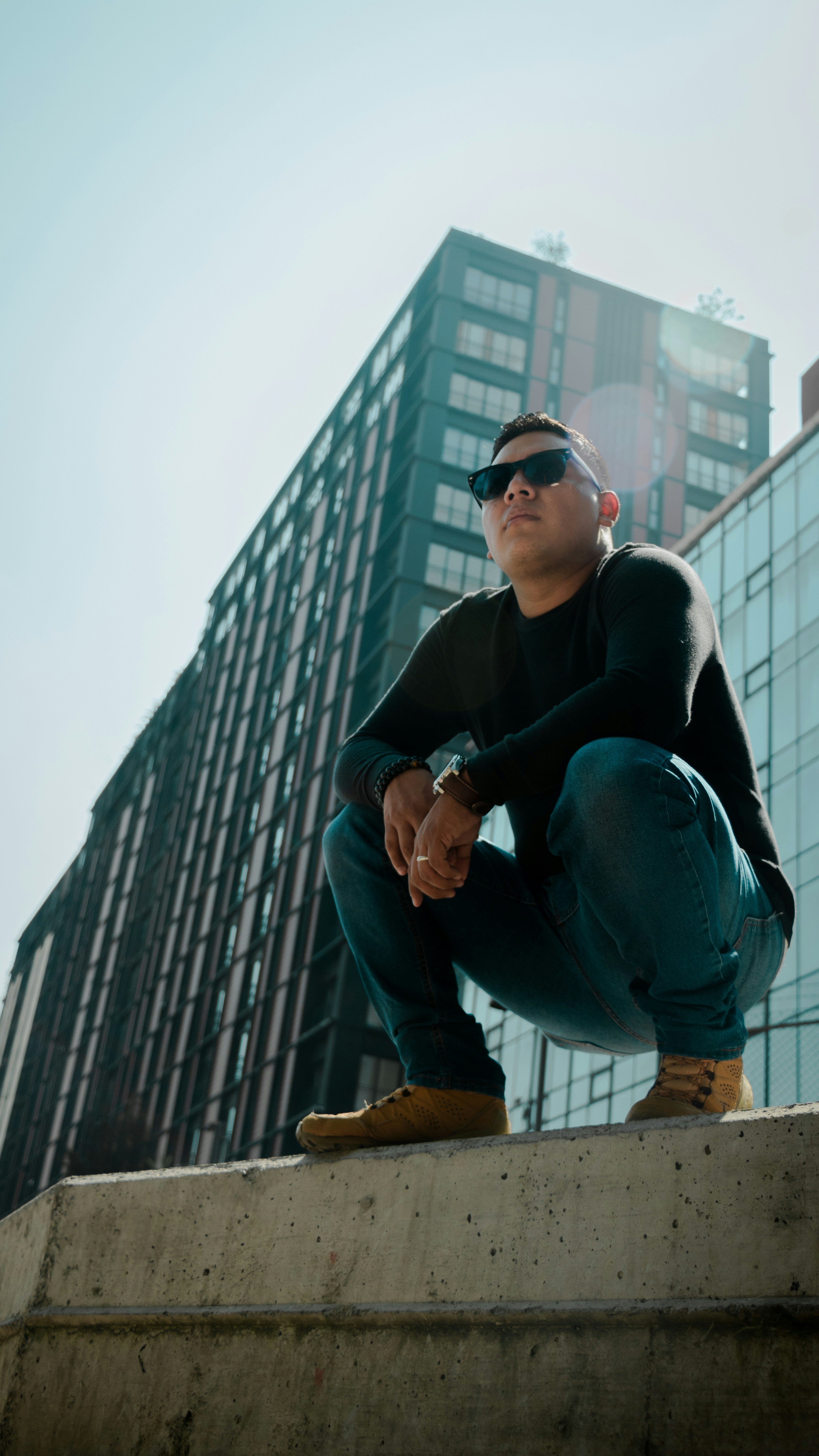 Un homme assis sur un rebord devant un grand immeuble photo – Photo ...