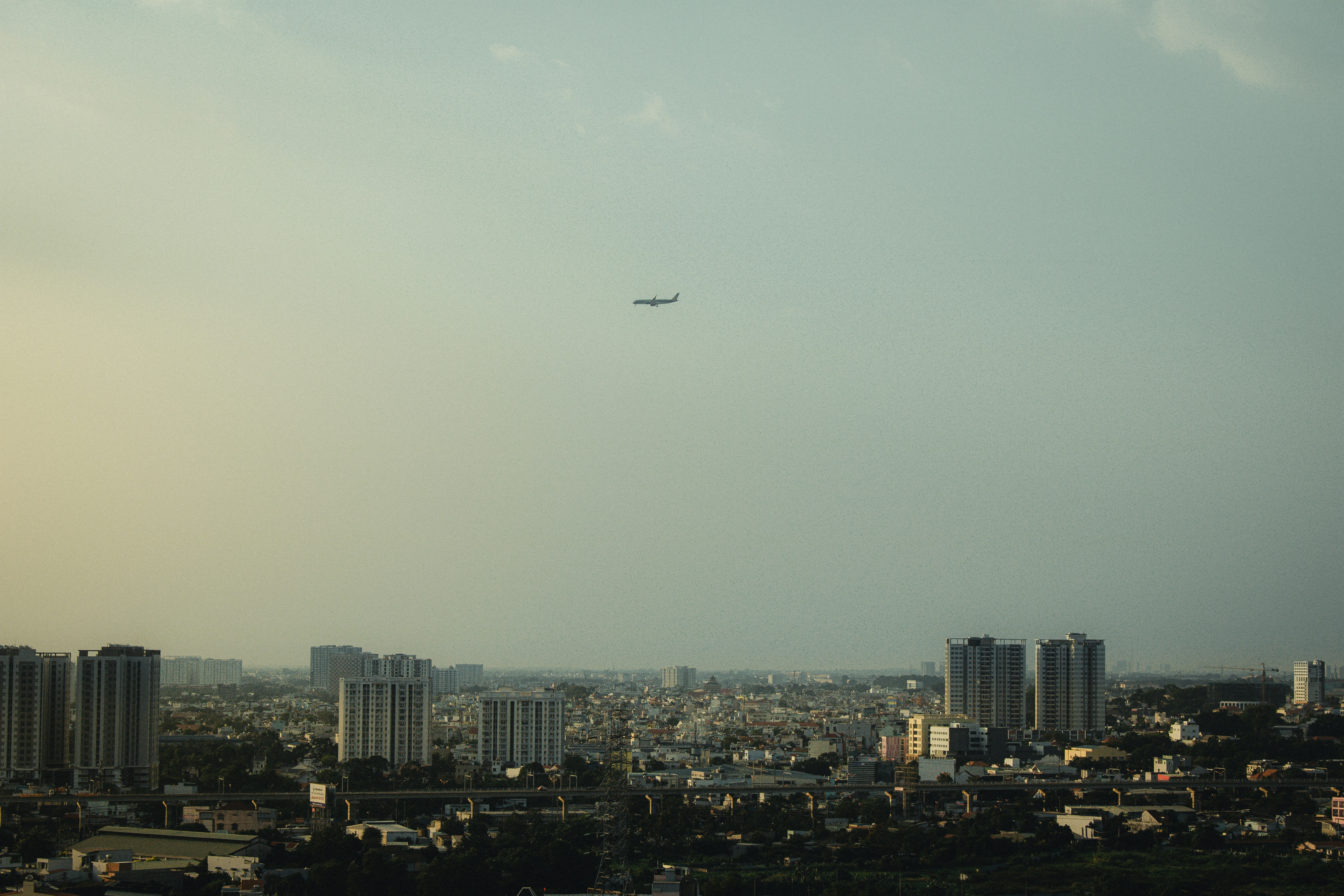 An airplane gliding through a hazy sky over a sprawling urban landscape, capturing the essence of city life and travel.
