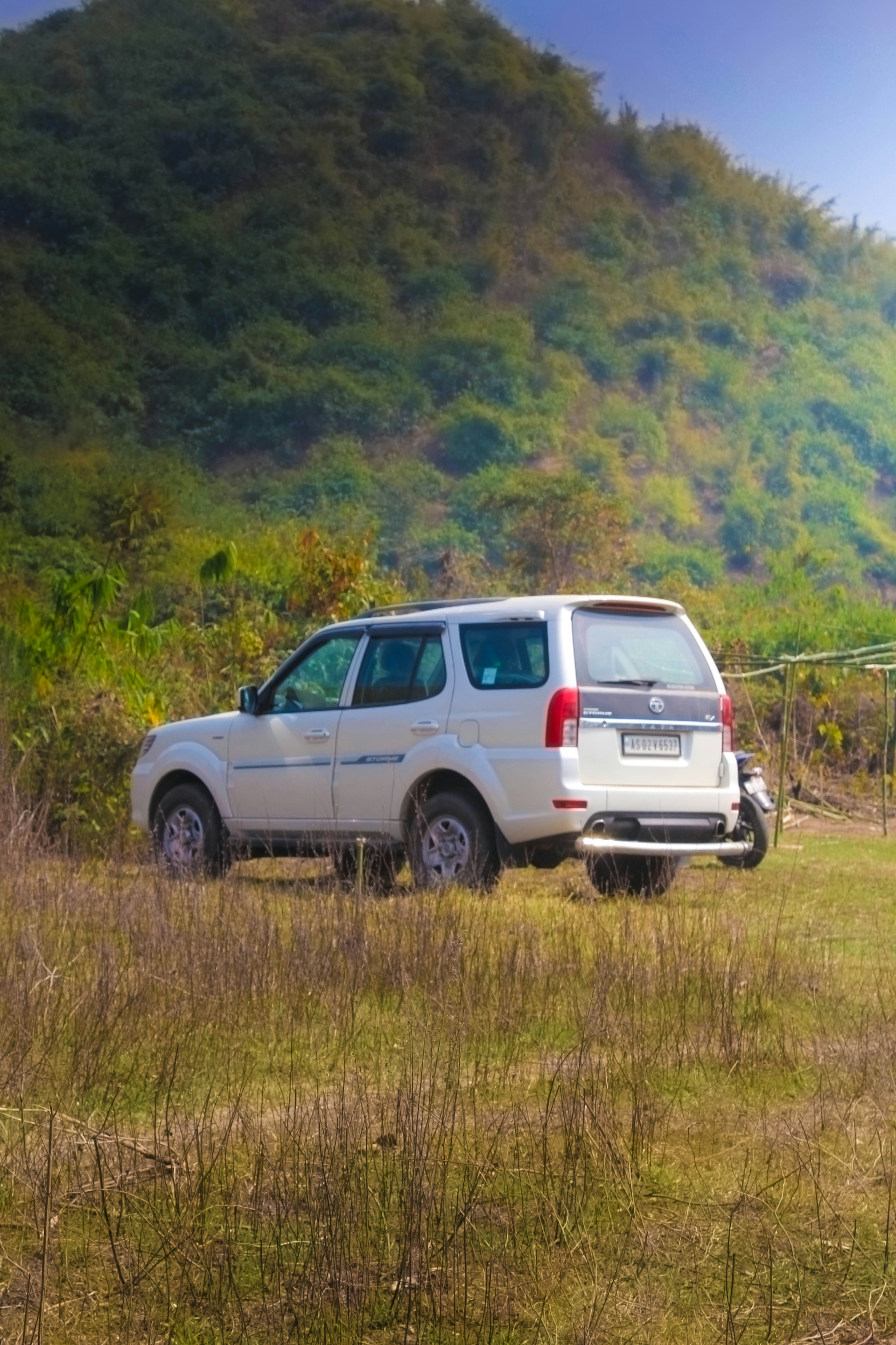 Field-side Scout: White SUV resting before a verdant hillside