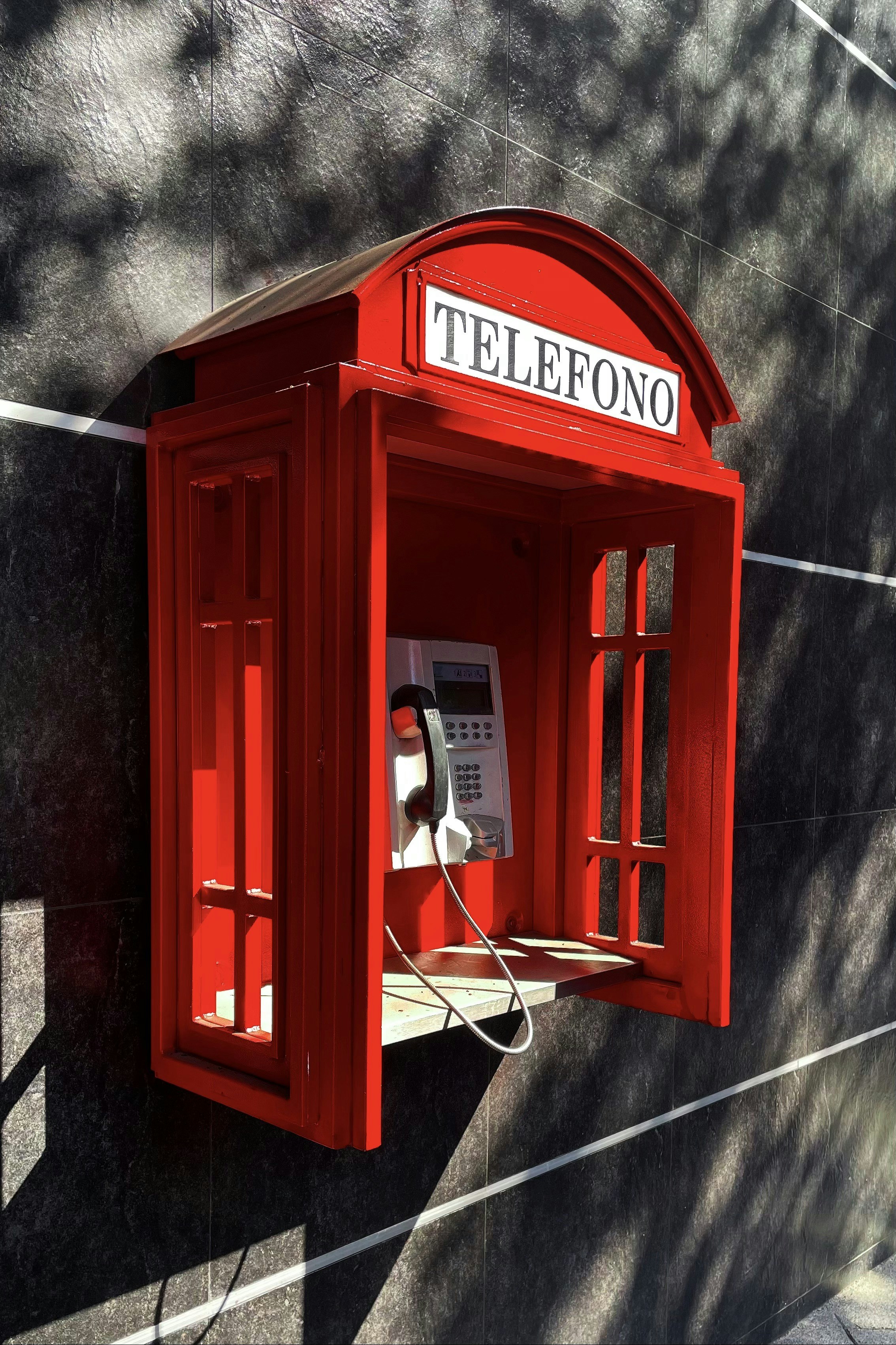 Red Telephone Booth in Stark Shadow: A Quiet Urban Icon