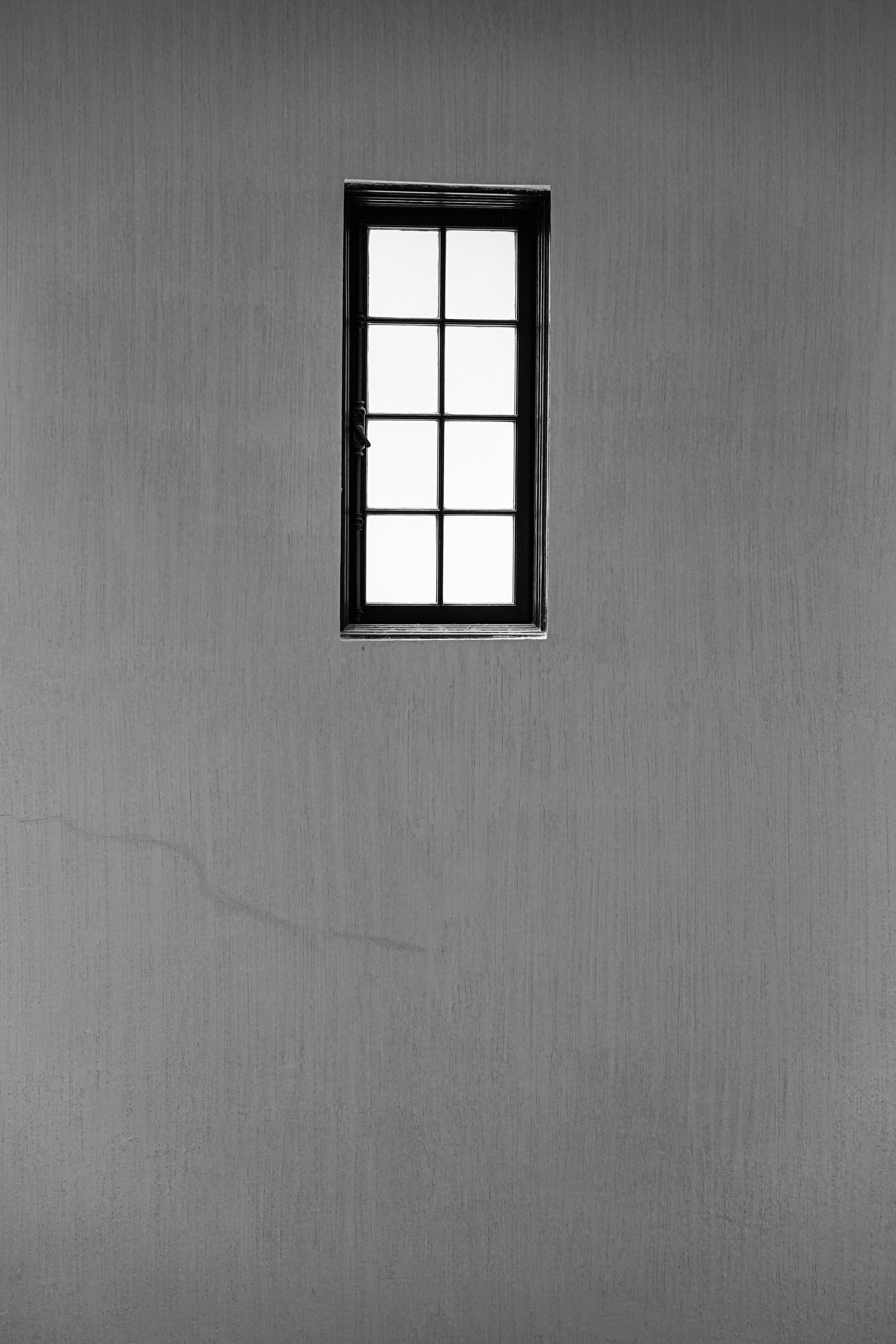 A solitary window set against a textured wall, inviting contemplation and a glimpse of the outside world.