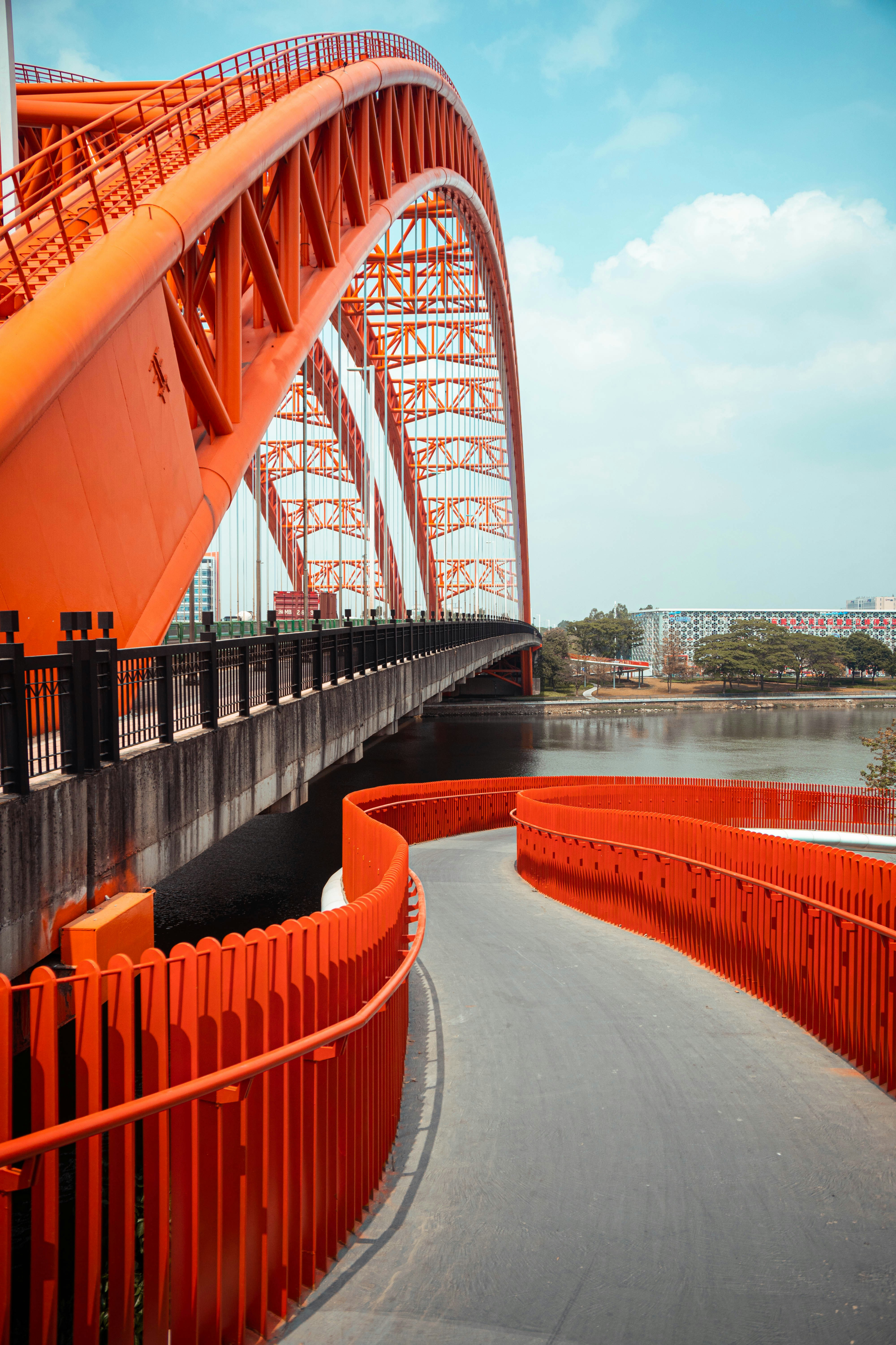Crimson Arc Over the Riverside: Spiraling Orange Bridge