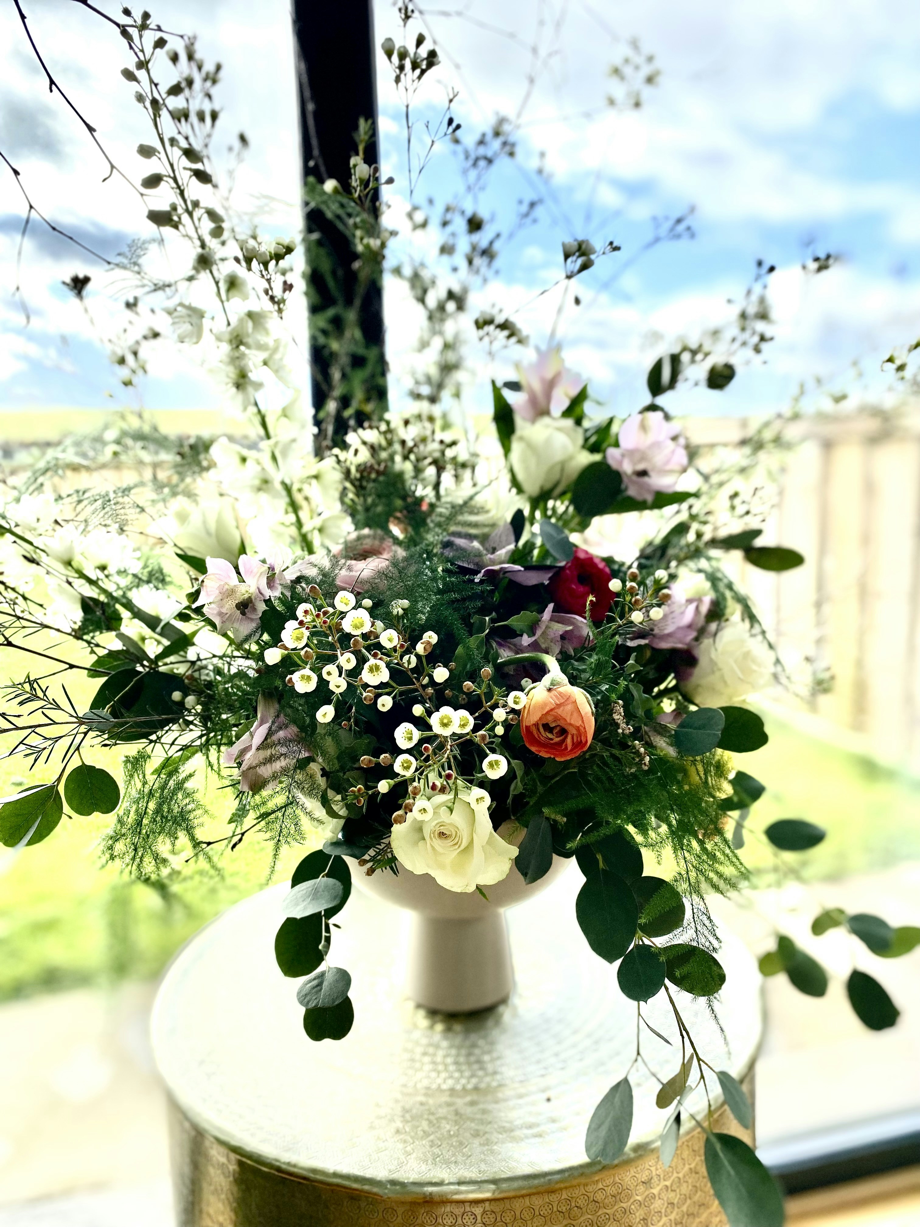 Sunlit Bouquet on a Glass Table: Roses, Daisies, and Greenery Framed by Window Light