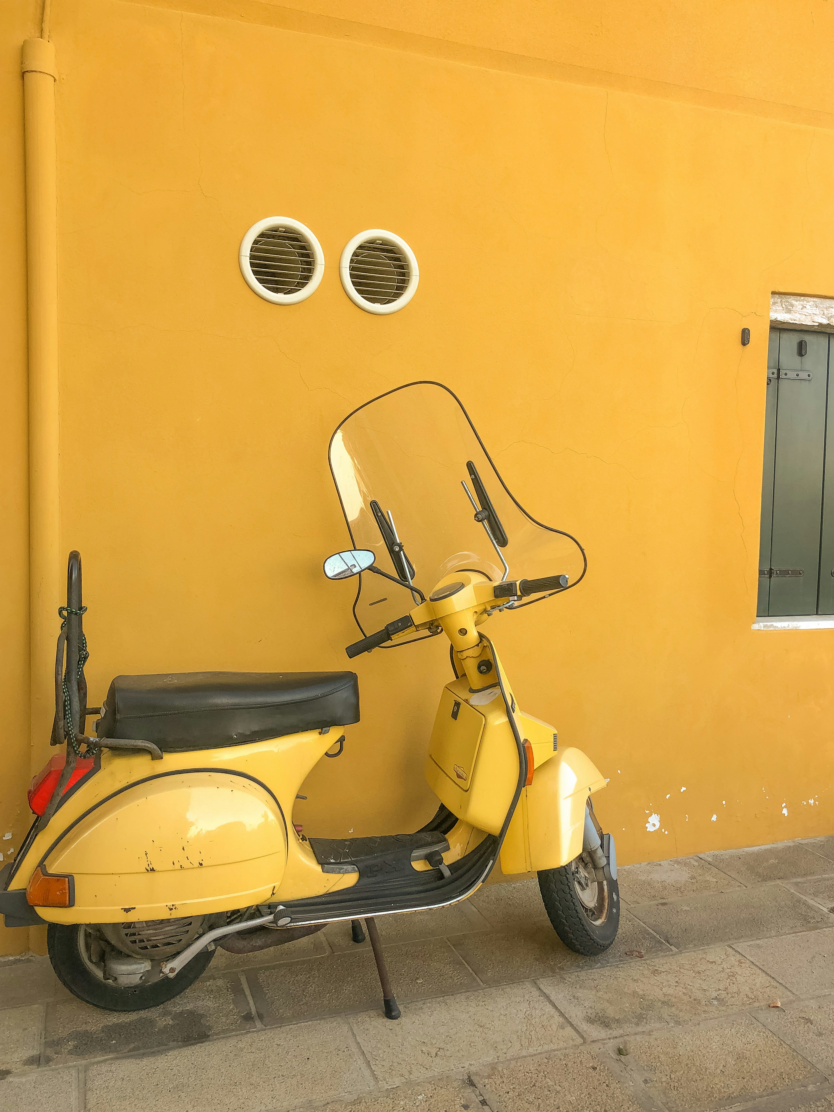 Sunlit Vespa Quietly Resting Before a Citrus-Yellow Wall