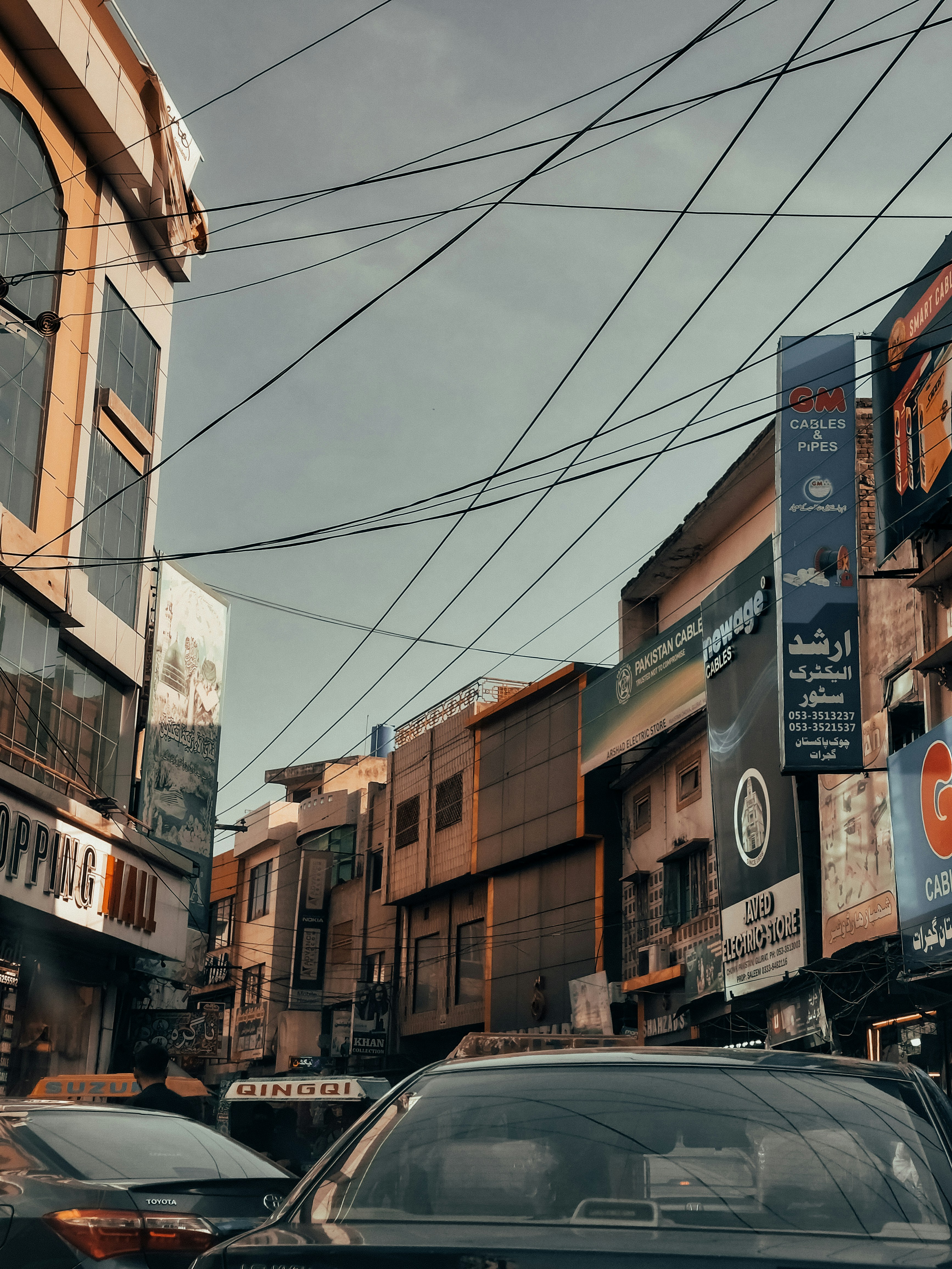 Busy urban street scene showcasing shops and overhead power lines, capturing the hustle and bustle of city life.