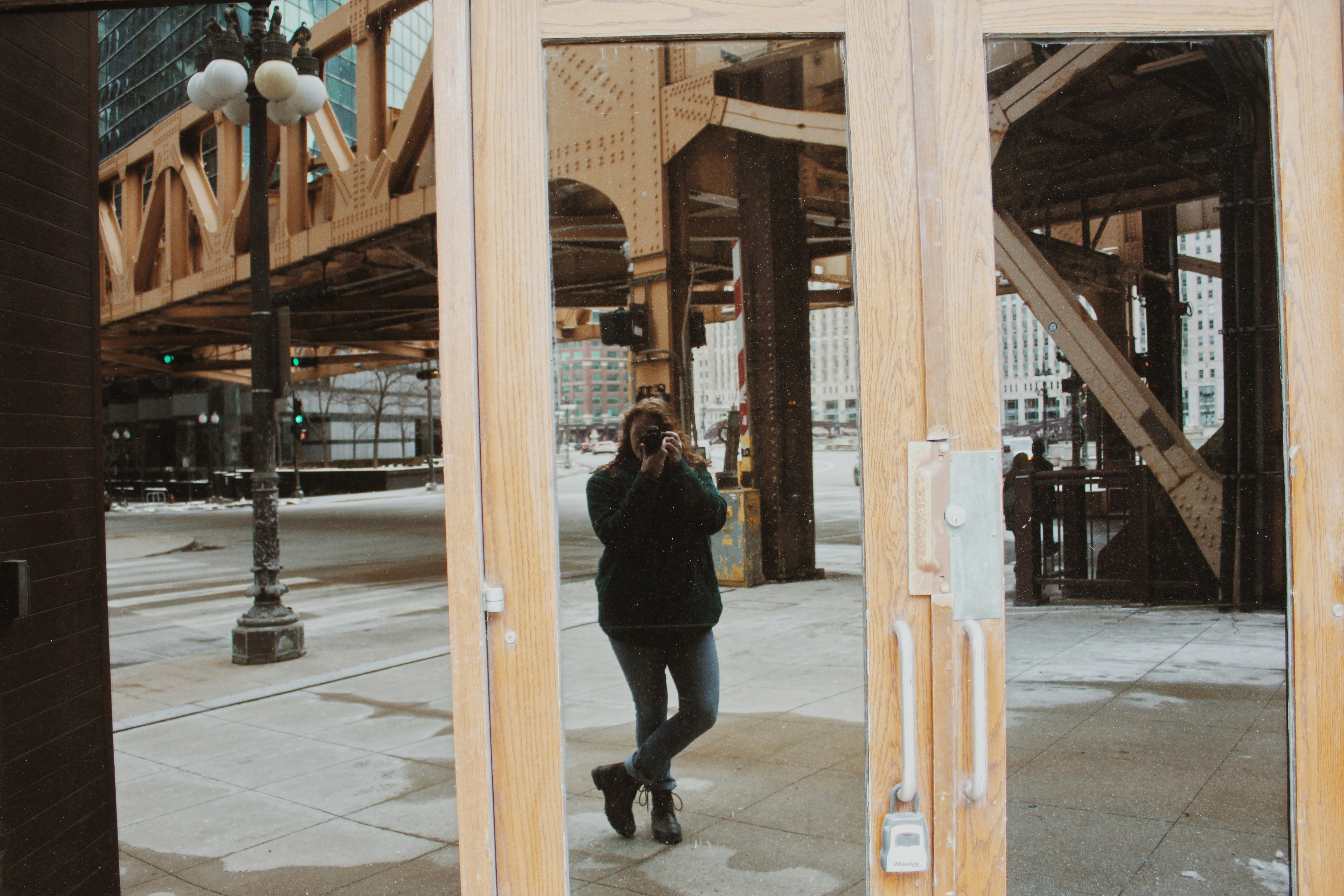 Through Glass and Timber: A Street Photographer Framed by an Urban Arcade