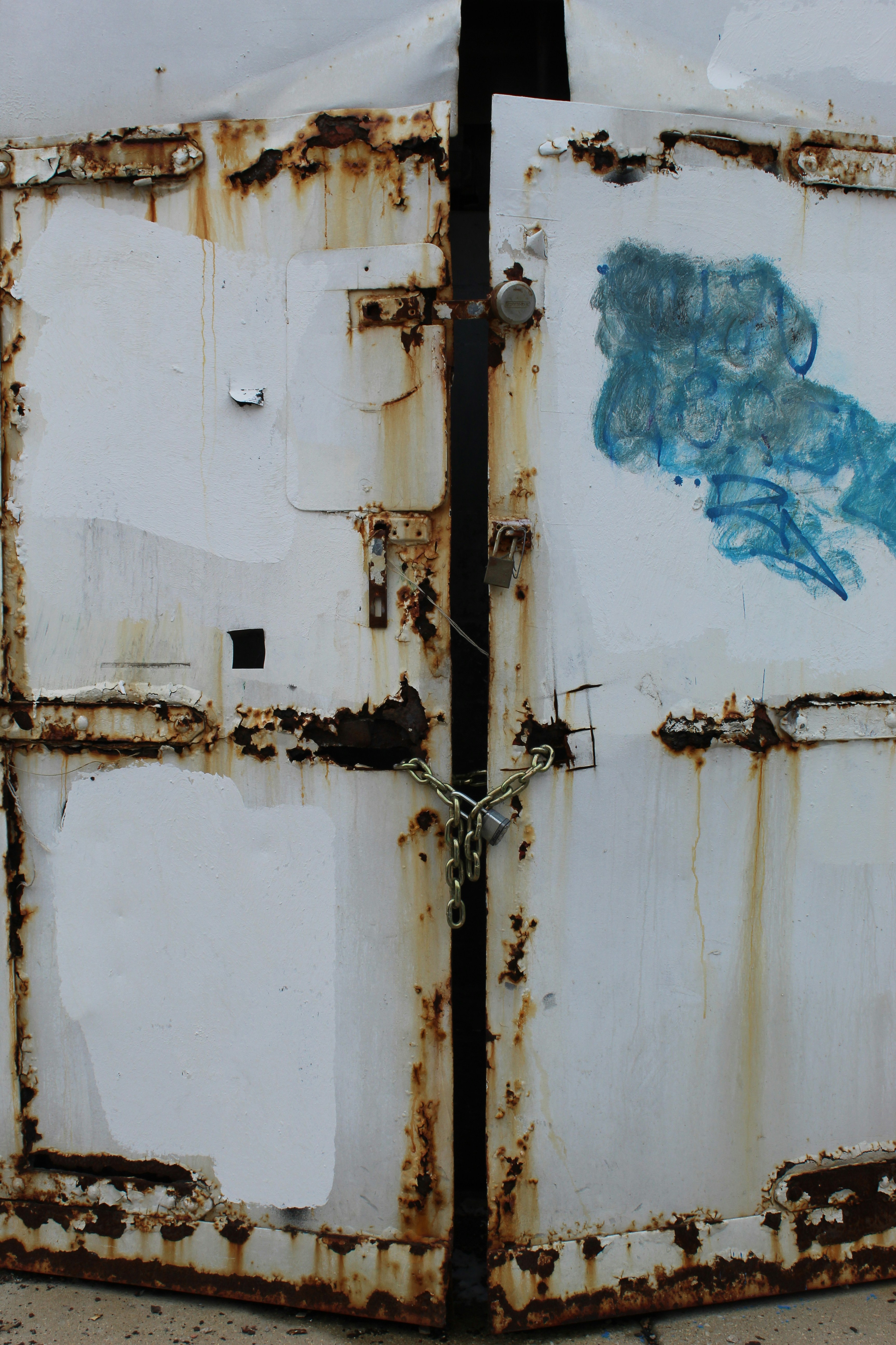 Rust-locked Gate: Symmetrical Doorway with Chains and Blue Markings