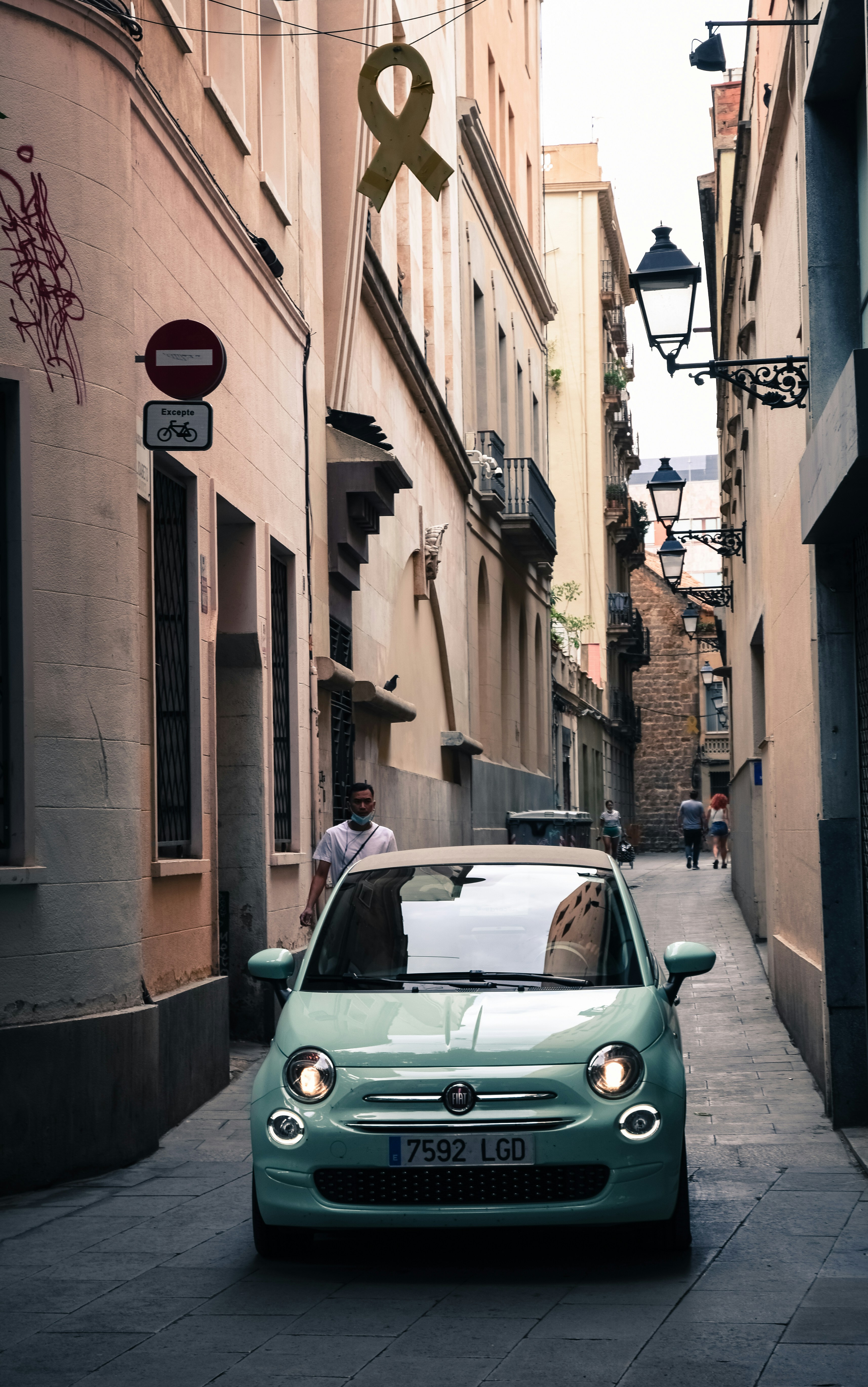 Mint Fiat 500 in a sunlit European alley under a hanging ribbon