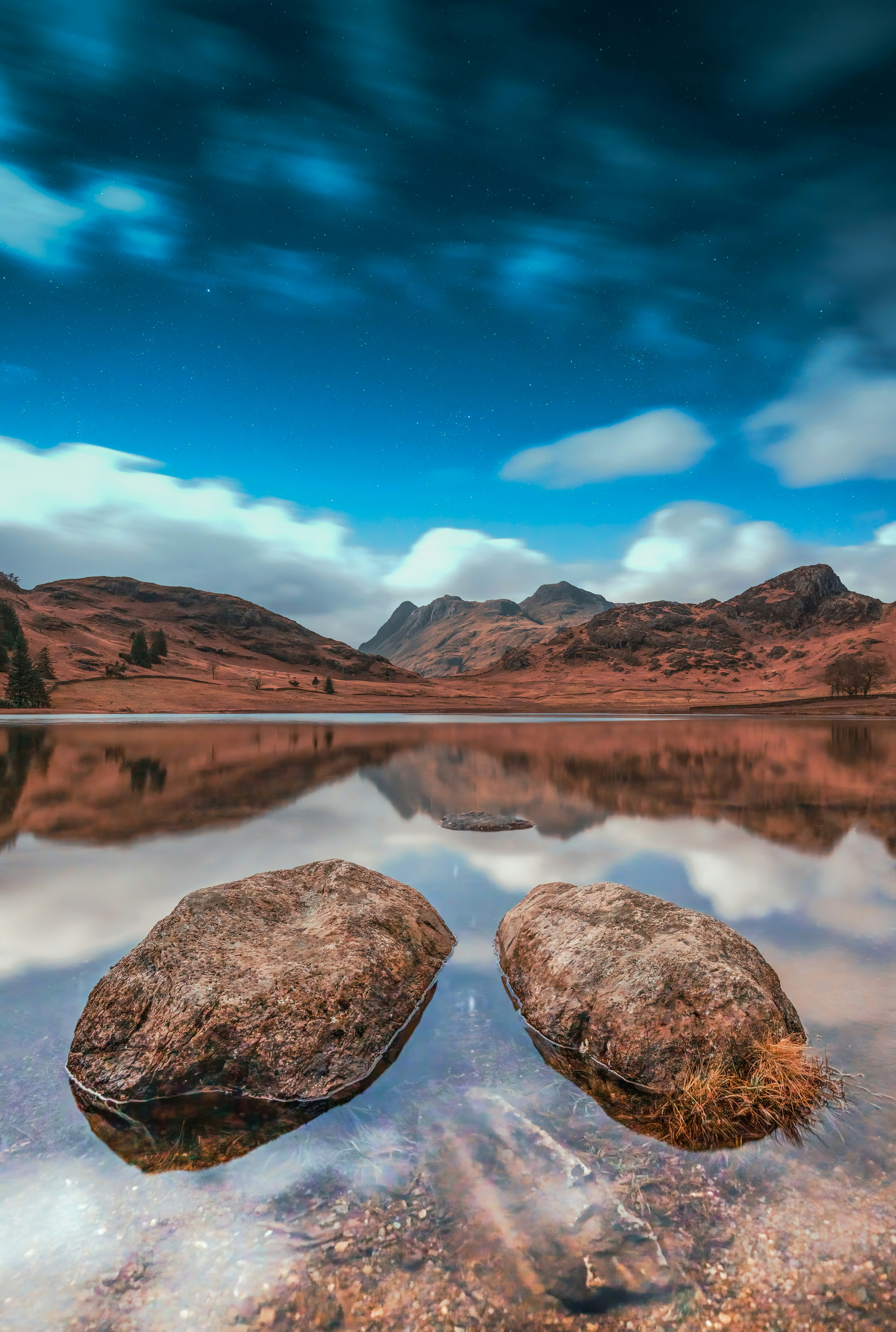 Foto Dos rocas sentadas en la cima de un lago bajo un cielo nublado ...