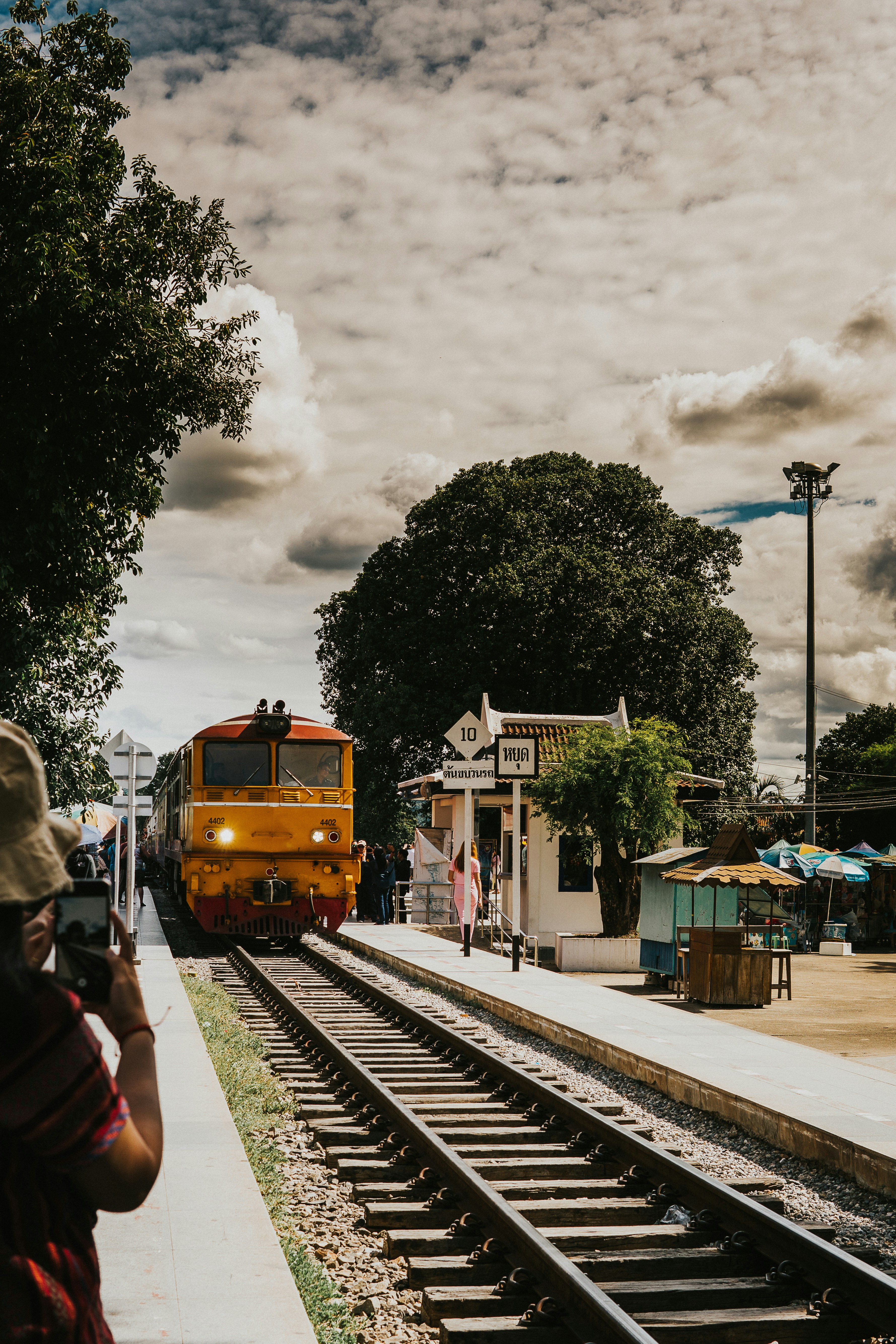 A yellow train traveling down train tracks next to a train station ...