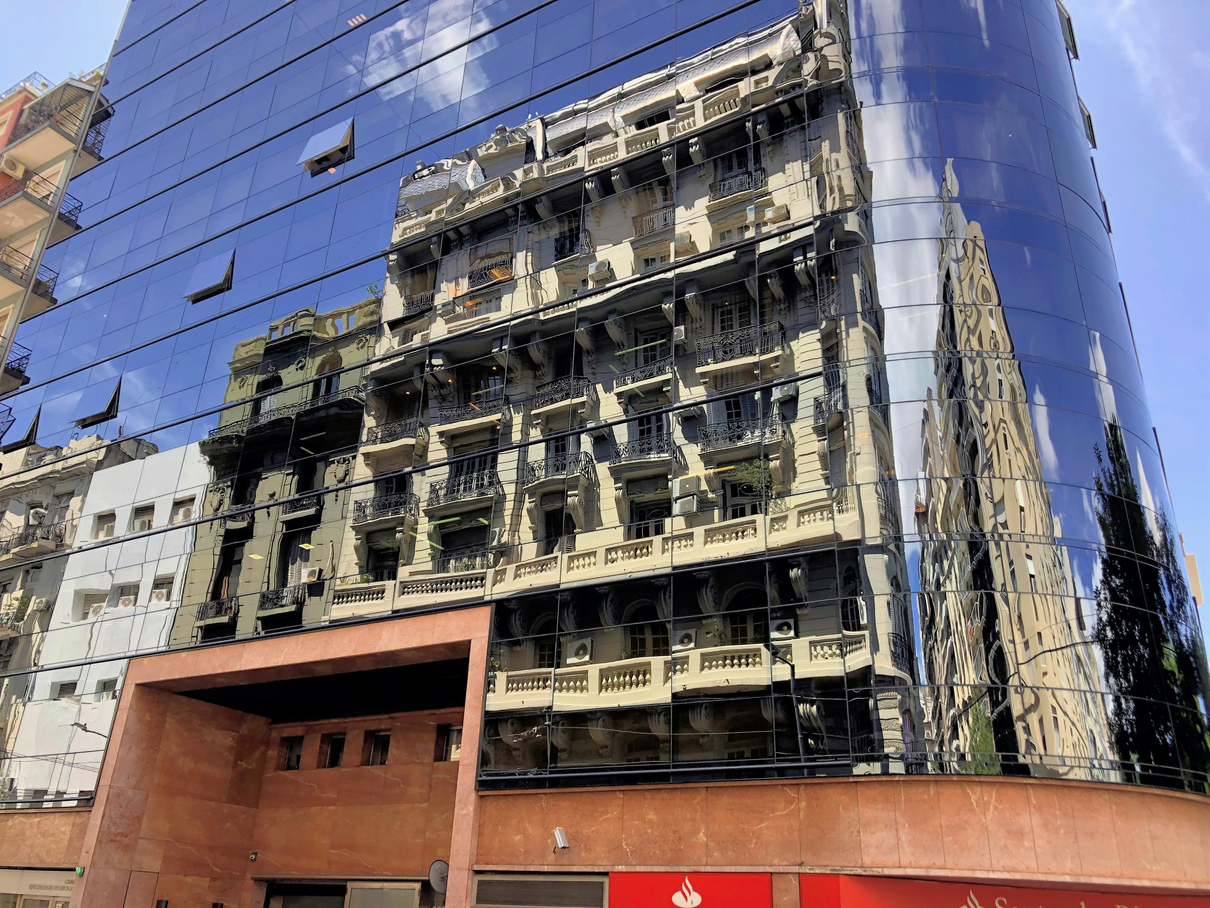 Modern glass building reflecting the intricate details of a historic facade, showcasing a blend of architectural styles.