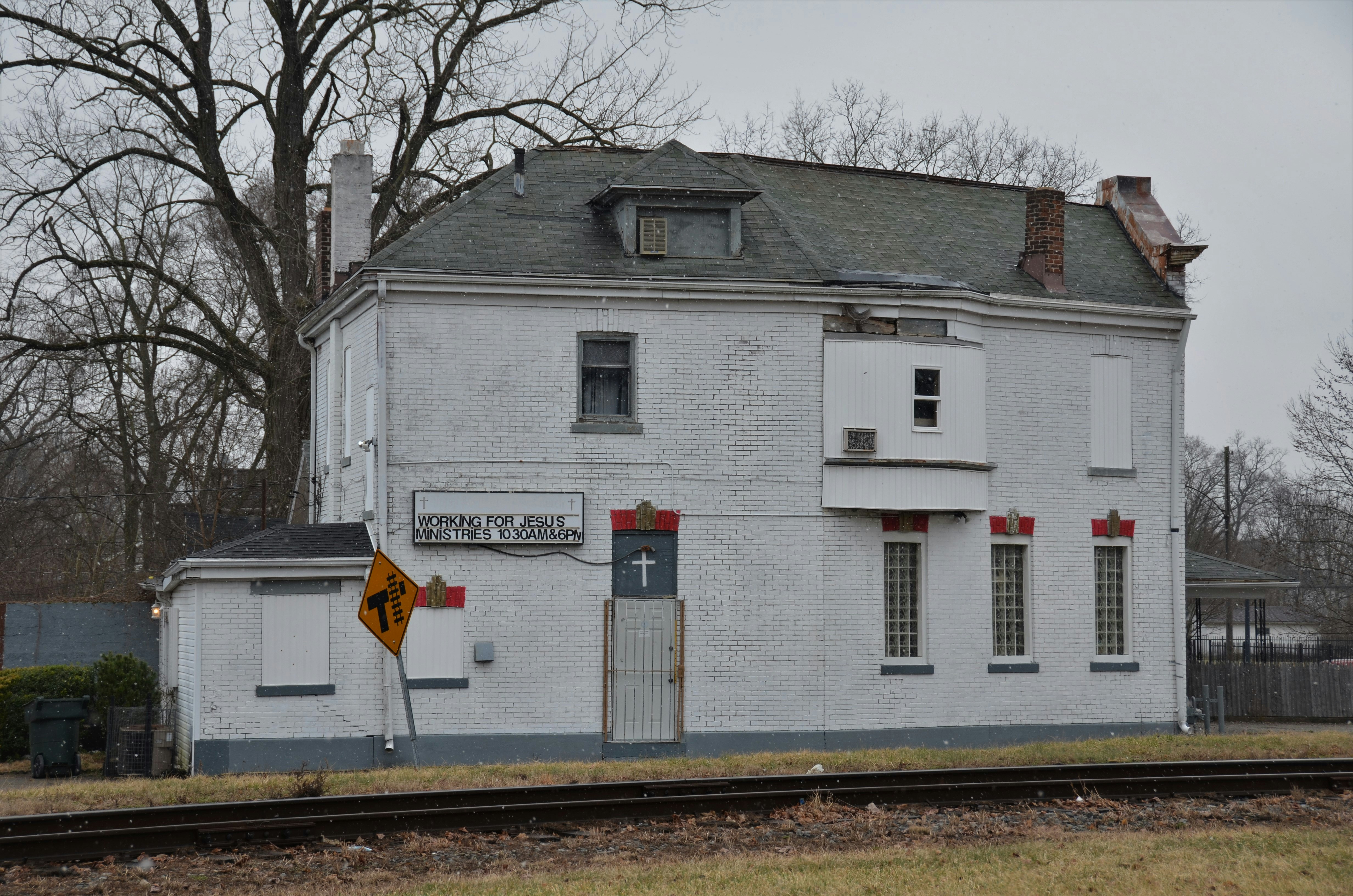 A white brick building with a railroad track in front of it photo ...