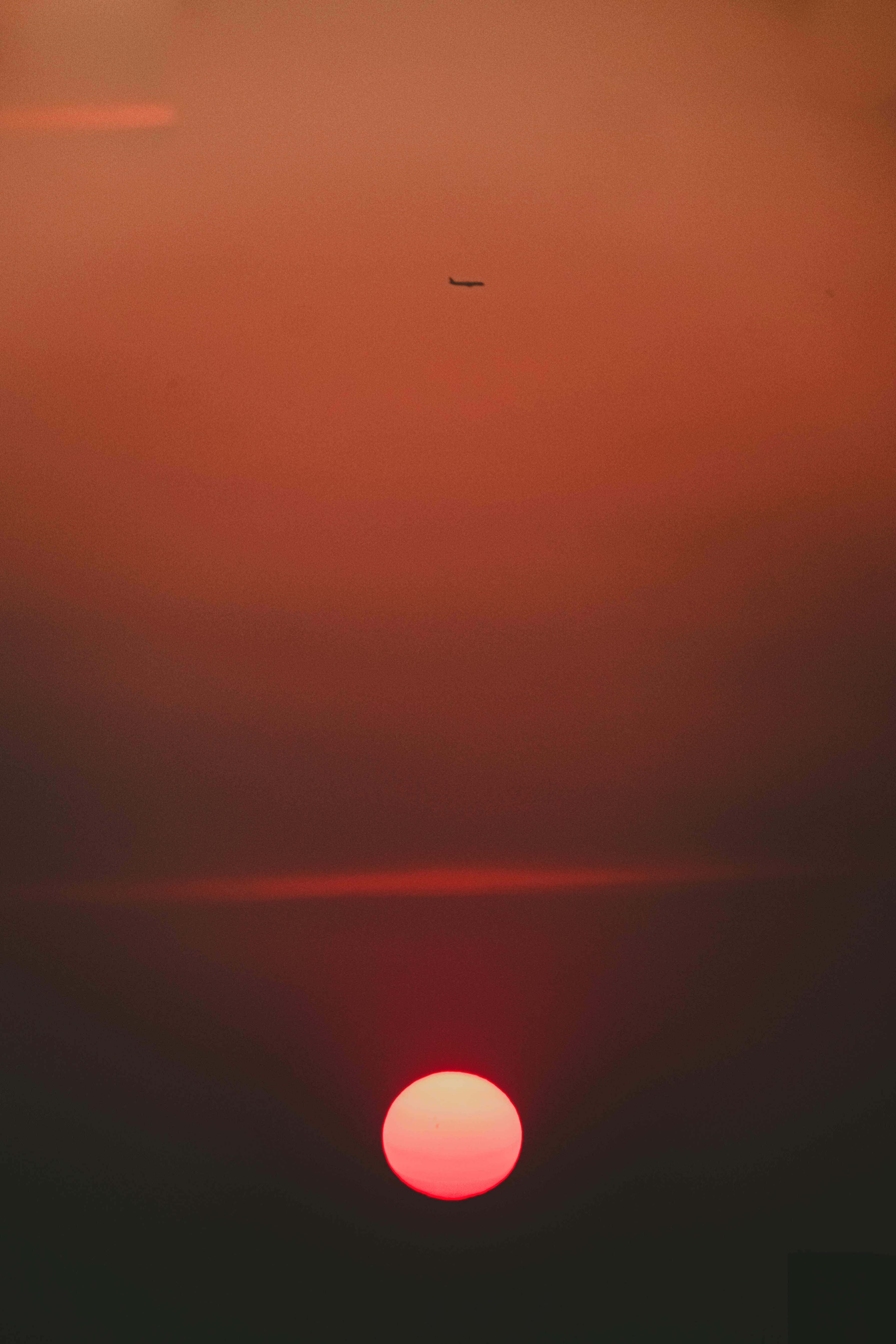 Crimson Horizon: A Lone Plane Crossing a Quiet Dusk