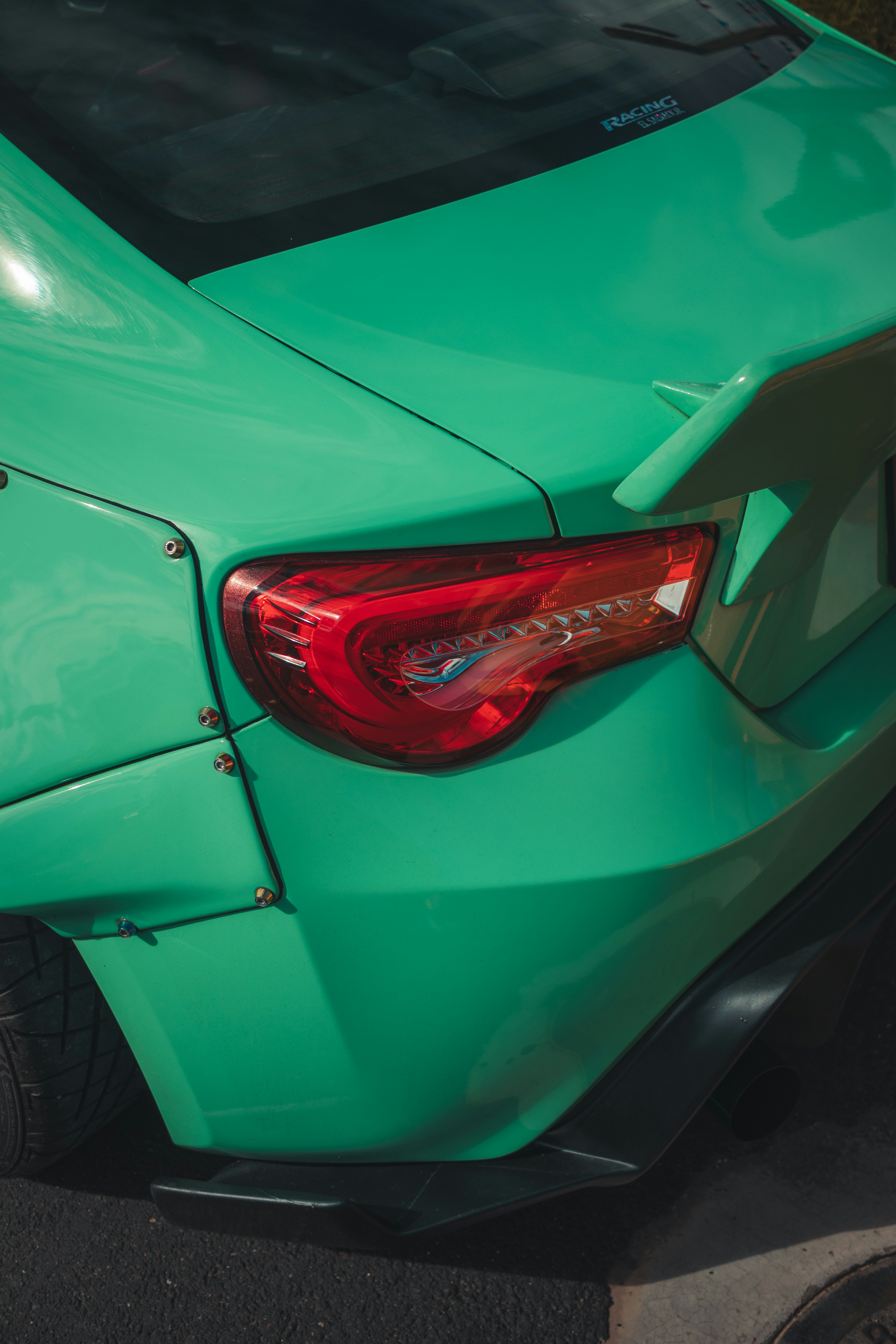 Verdant Rear: riveted seams and a bold tail light on a lime-green sports sedan