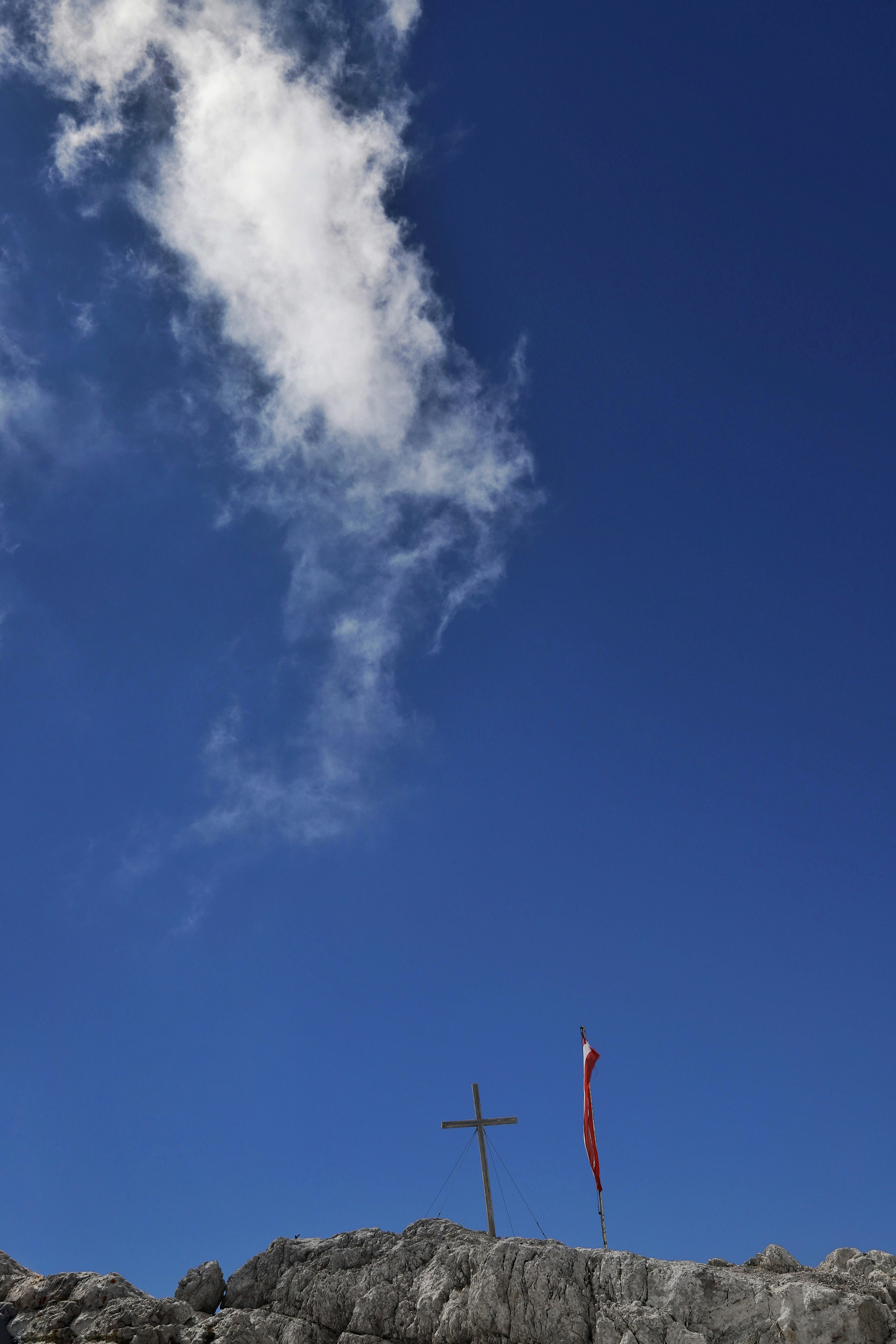 Cross on a Wind-Swept Alpine Ridge Beneath a Pristine Blue Sky