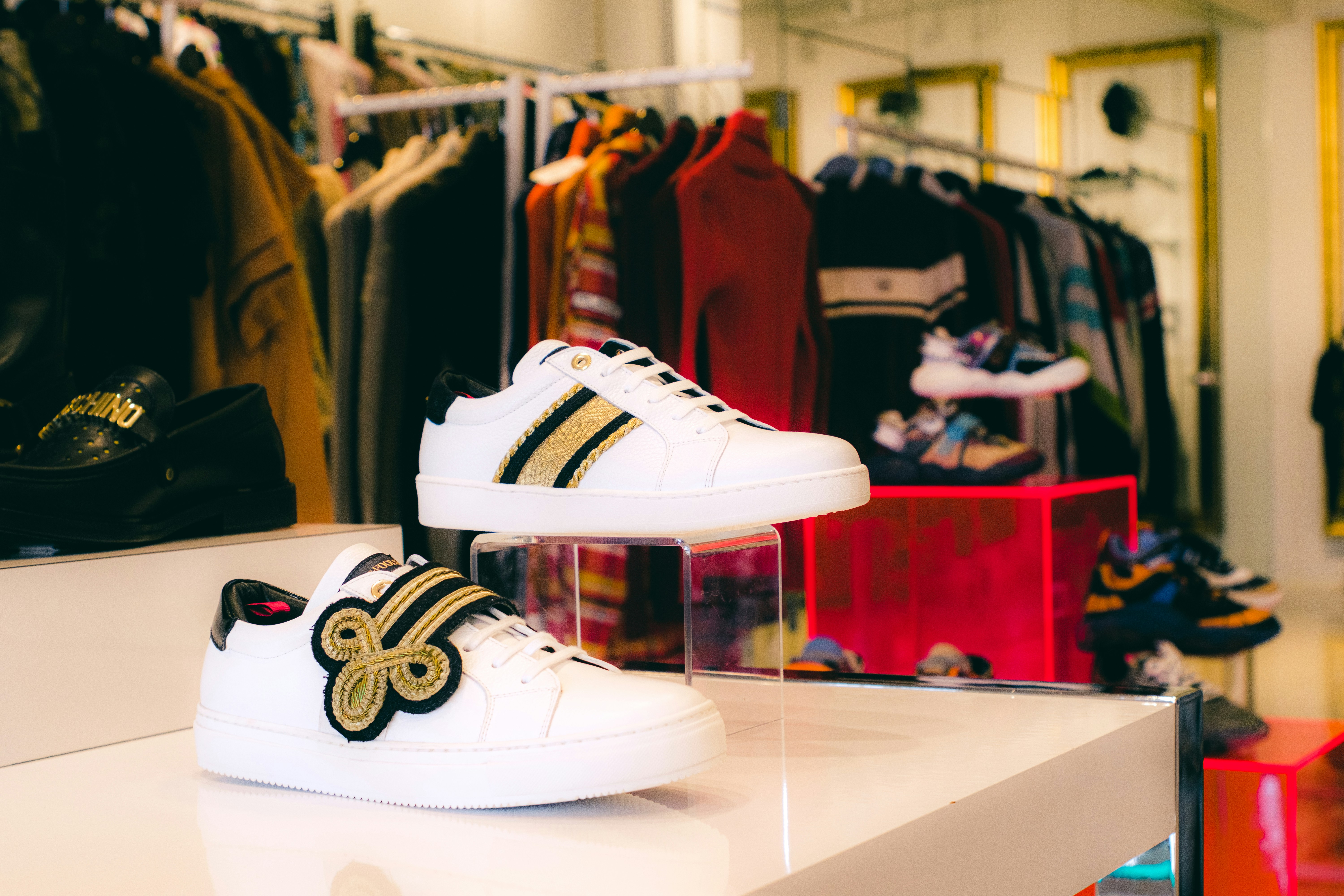 Luxe Minimalism: White sneakers with gold embroidery on a glossy pedestal in a boutique display