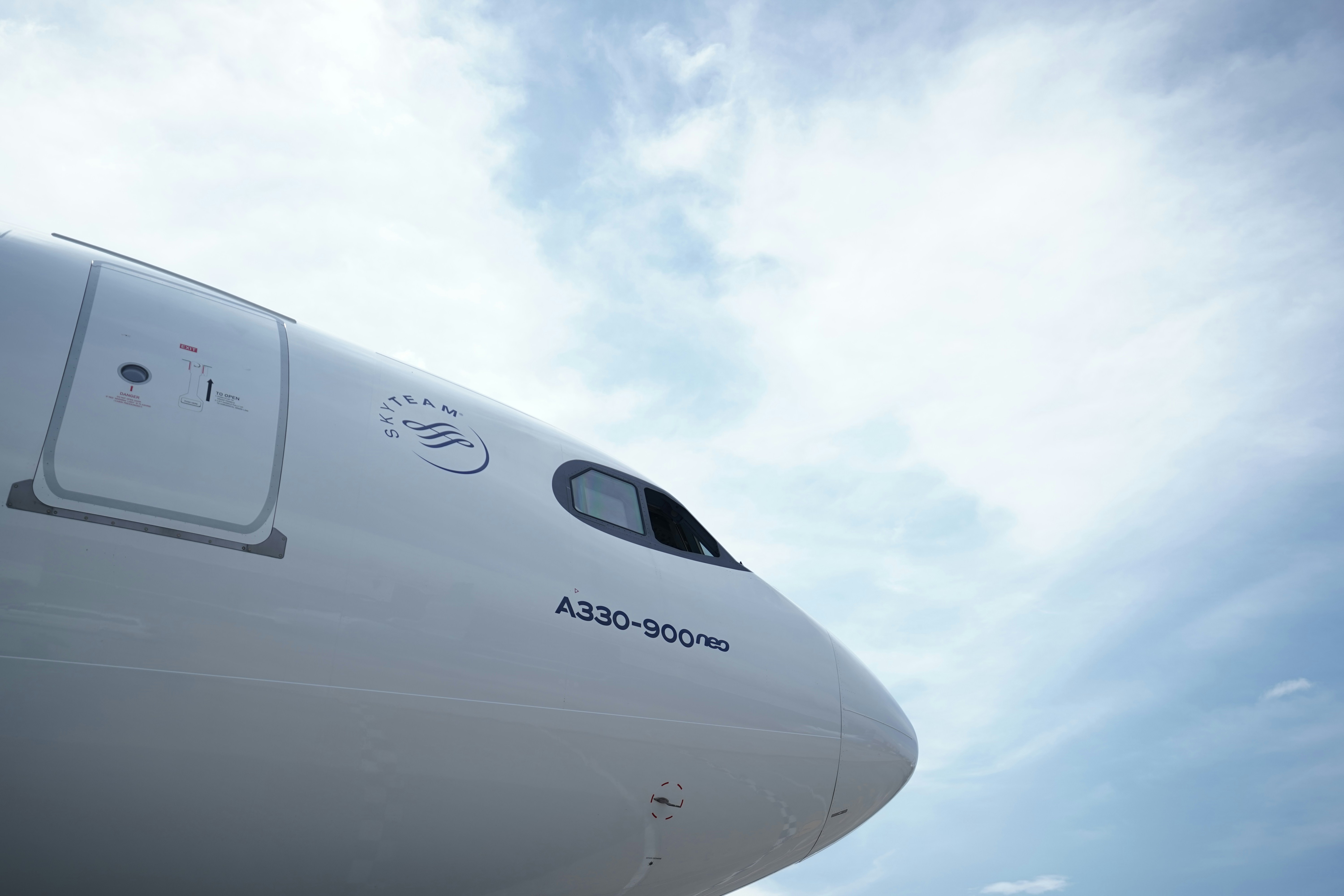 Close-up of an Airbus A330-900neo showcasing its sleek nose and modern design against a bright sky.