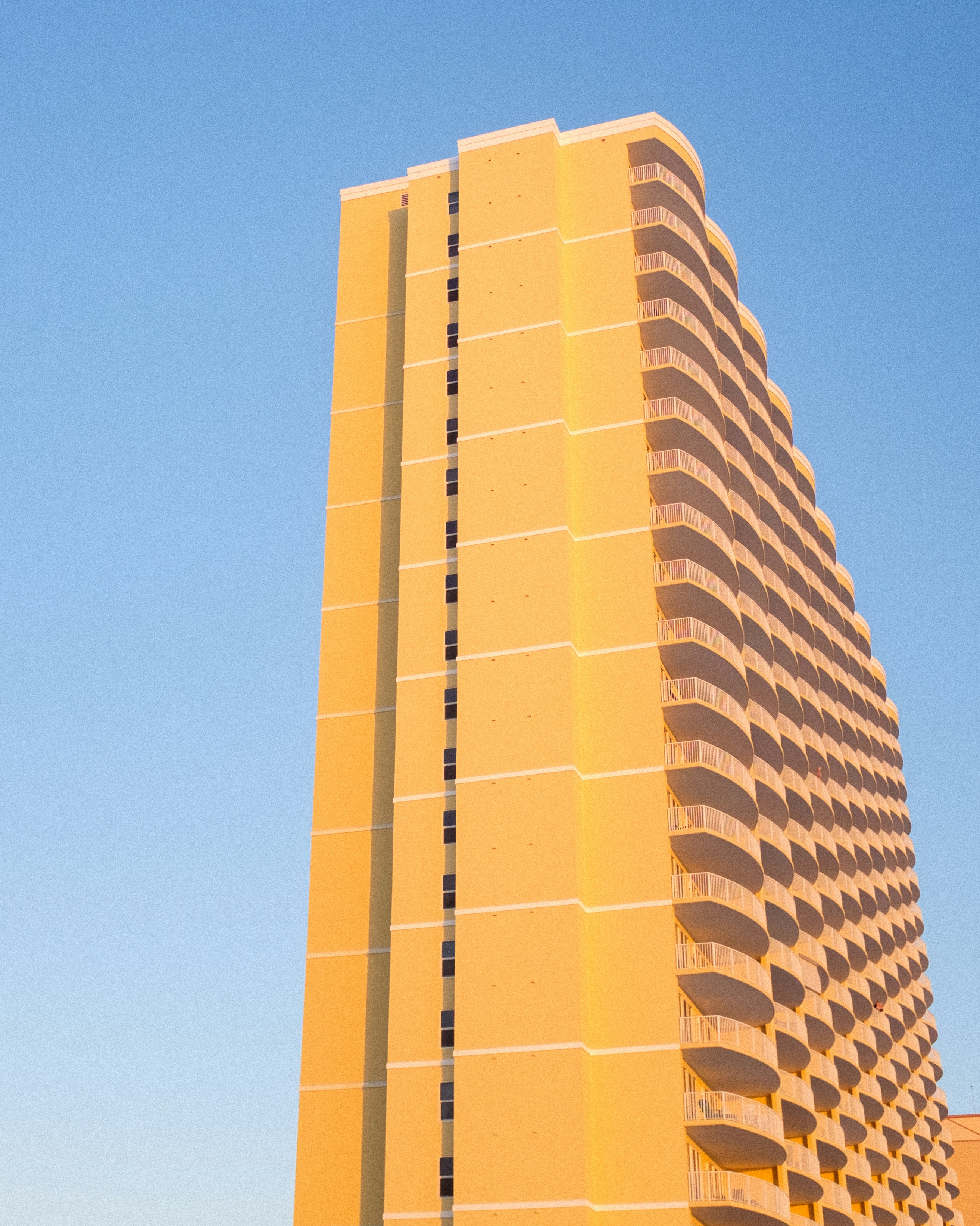 A tall yellow building sitting next to a parking lot photo – Free ...