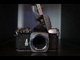 Center Stage: Vintage 35mm SLR with bare lens on a dim pedestal