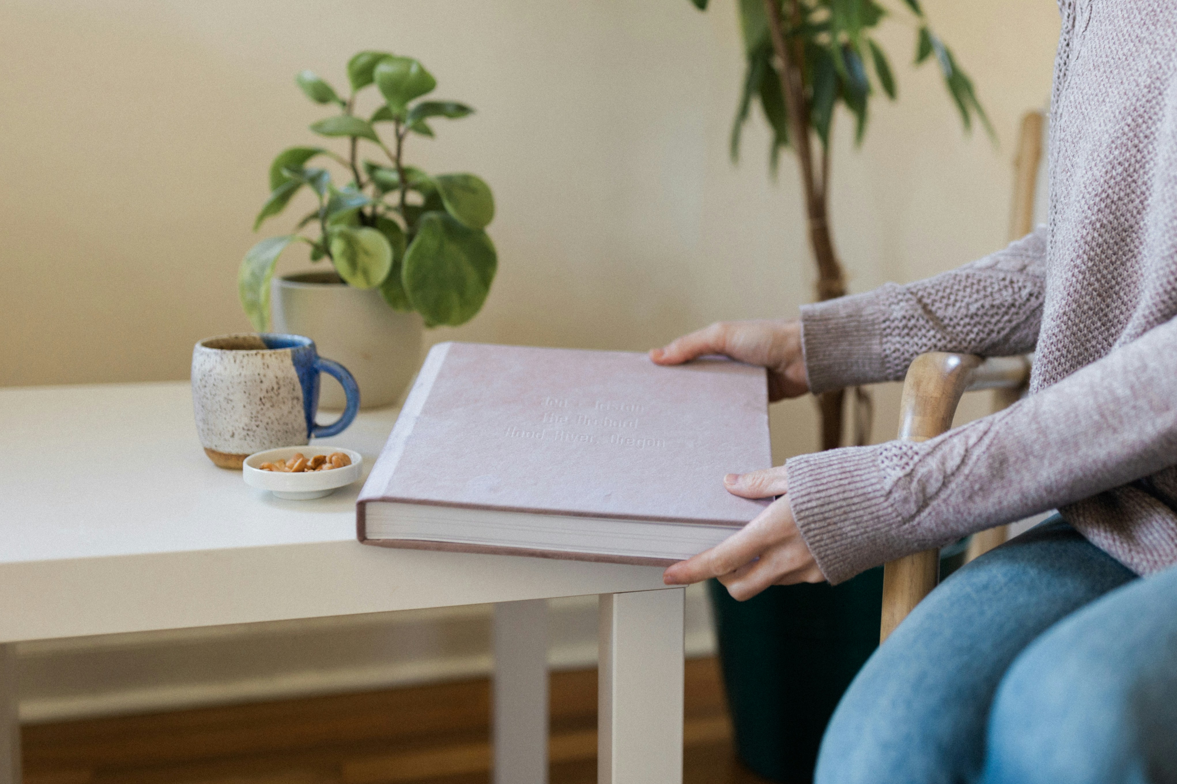 A woman sitting at a table holding a book photo – Free Human Image on ...