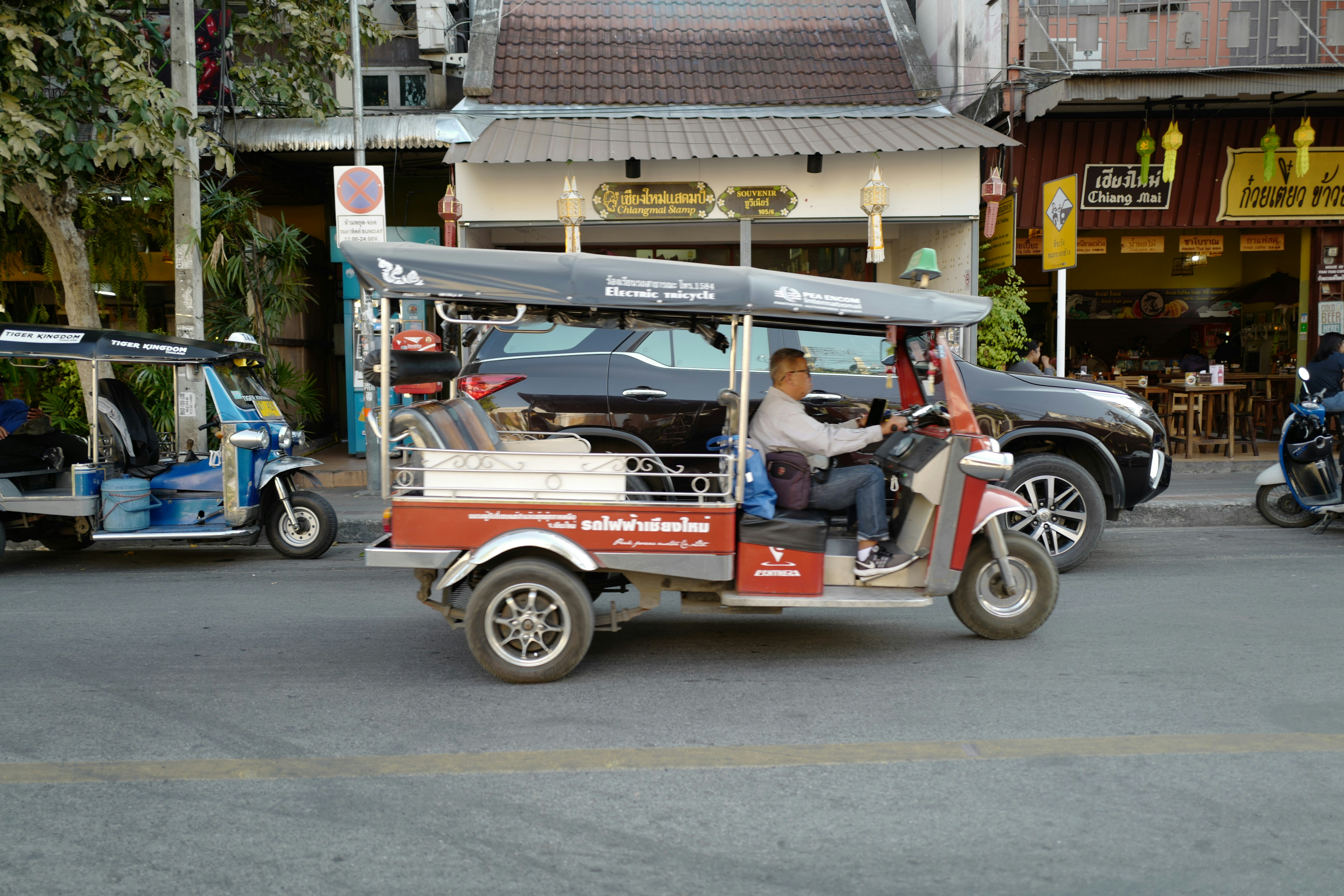 A tuk-tuk navigates a bustling street, embodying the vibrant essence of local transportation amidst urban life.