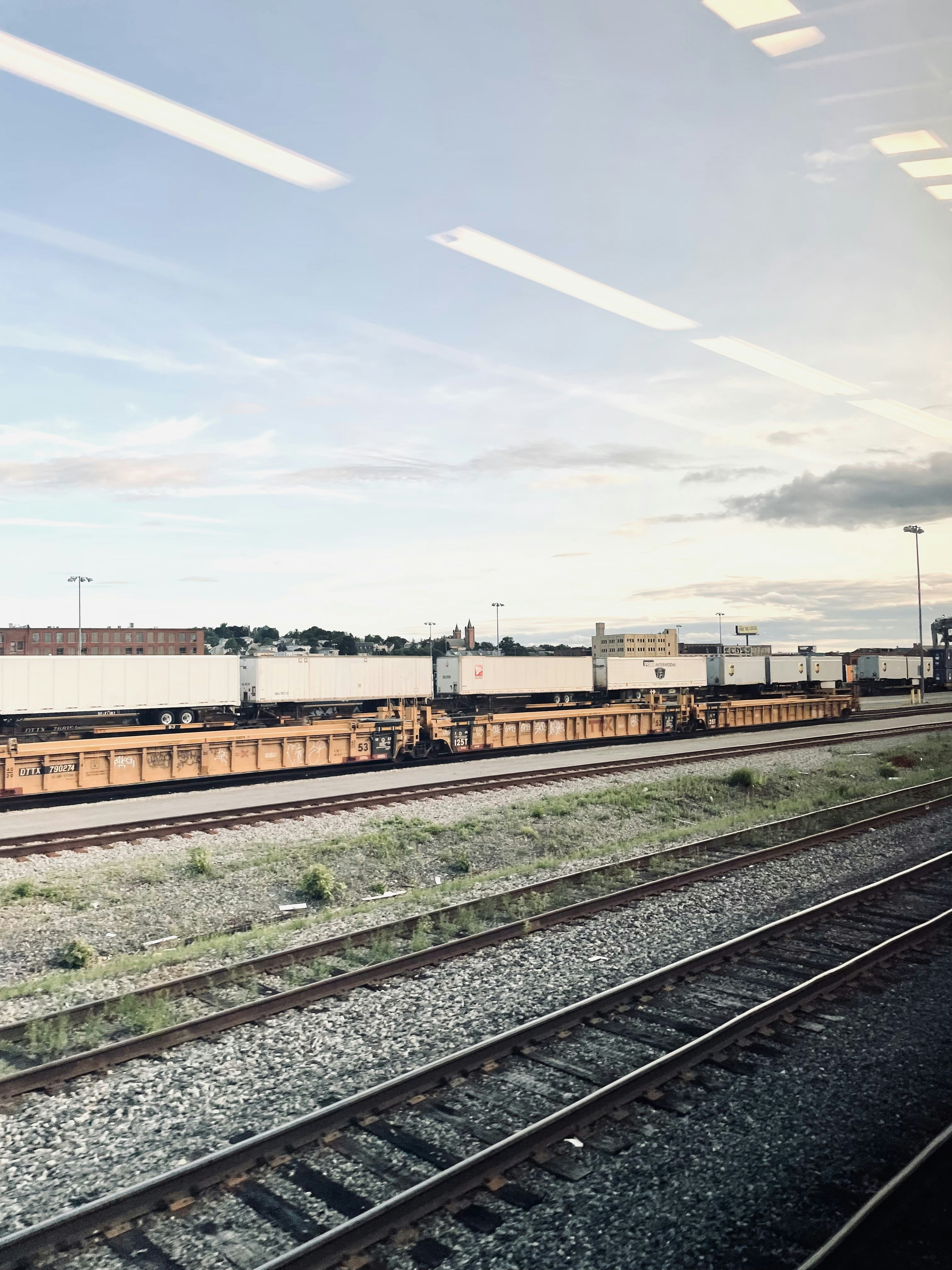 Freight train cars lined up on a railway track under a soft evening sky, showcasing the industrial landscape of transportation. 