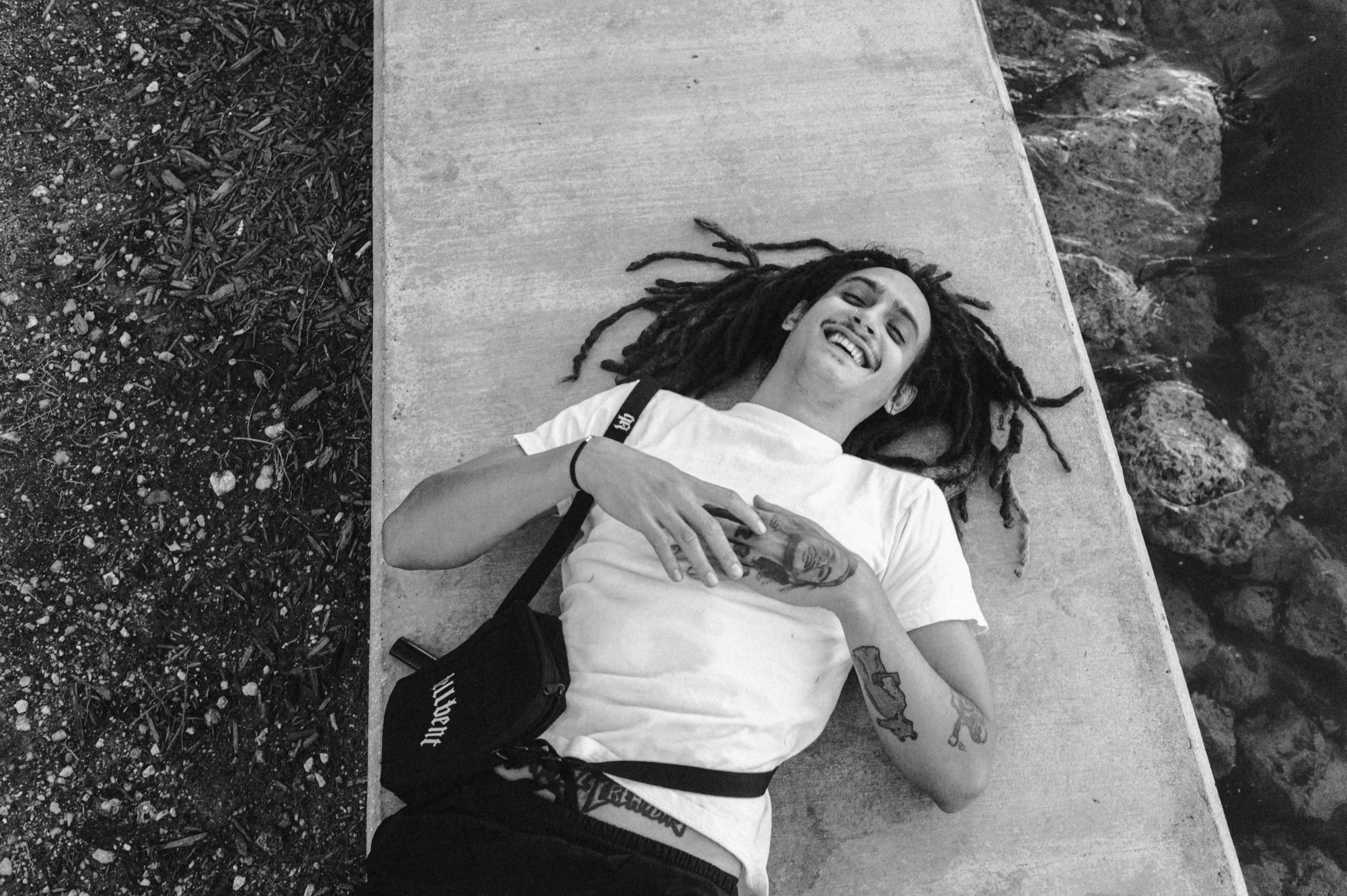A man with dreadlocks laying on the ground photo – Free Grey Image on ...