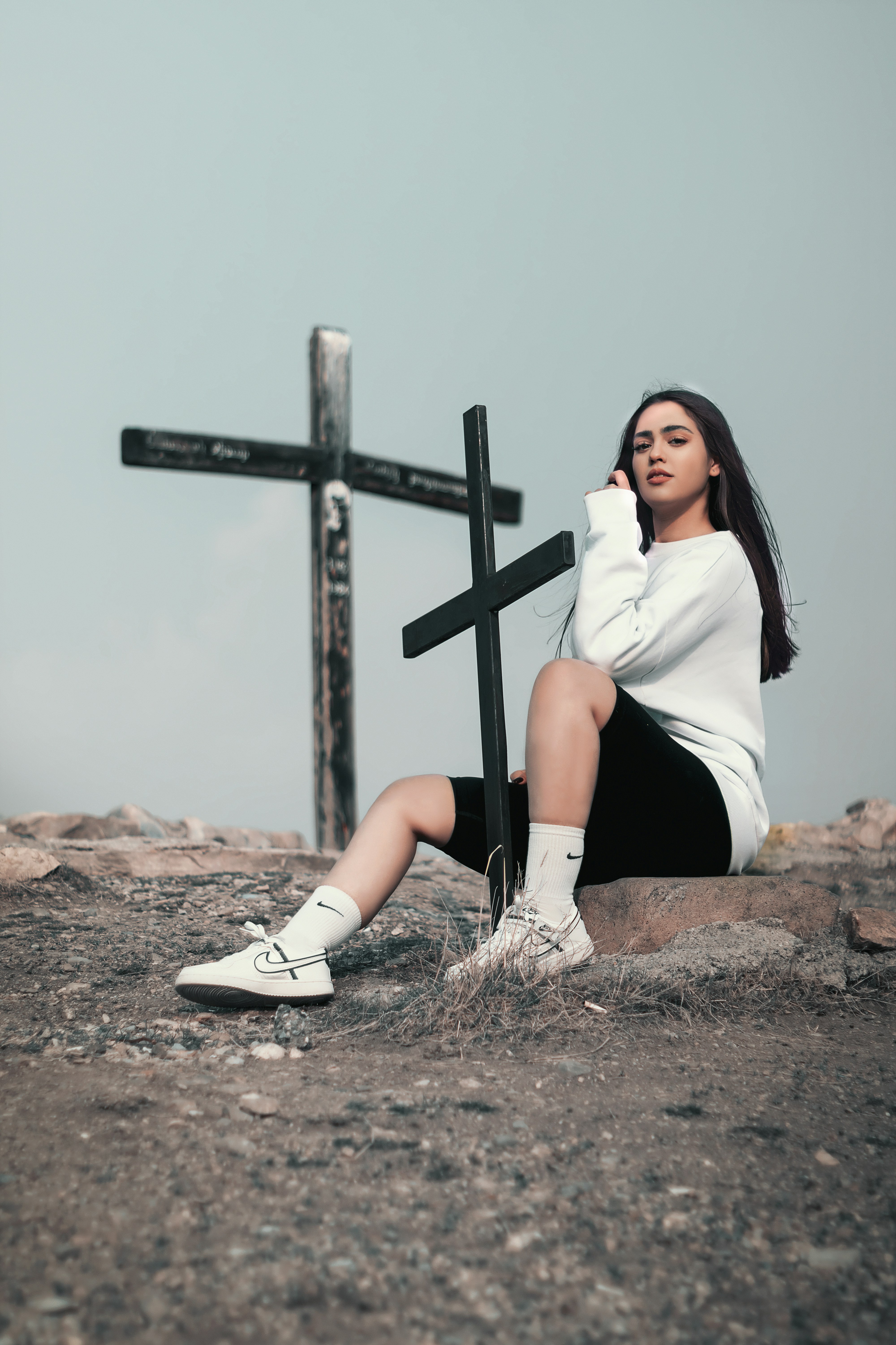 Solitary Portrait Beside Weathered Crosses on a Windy Ridge