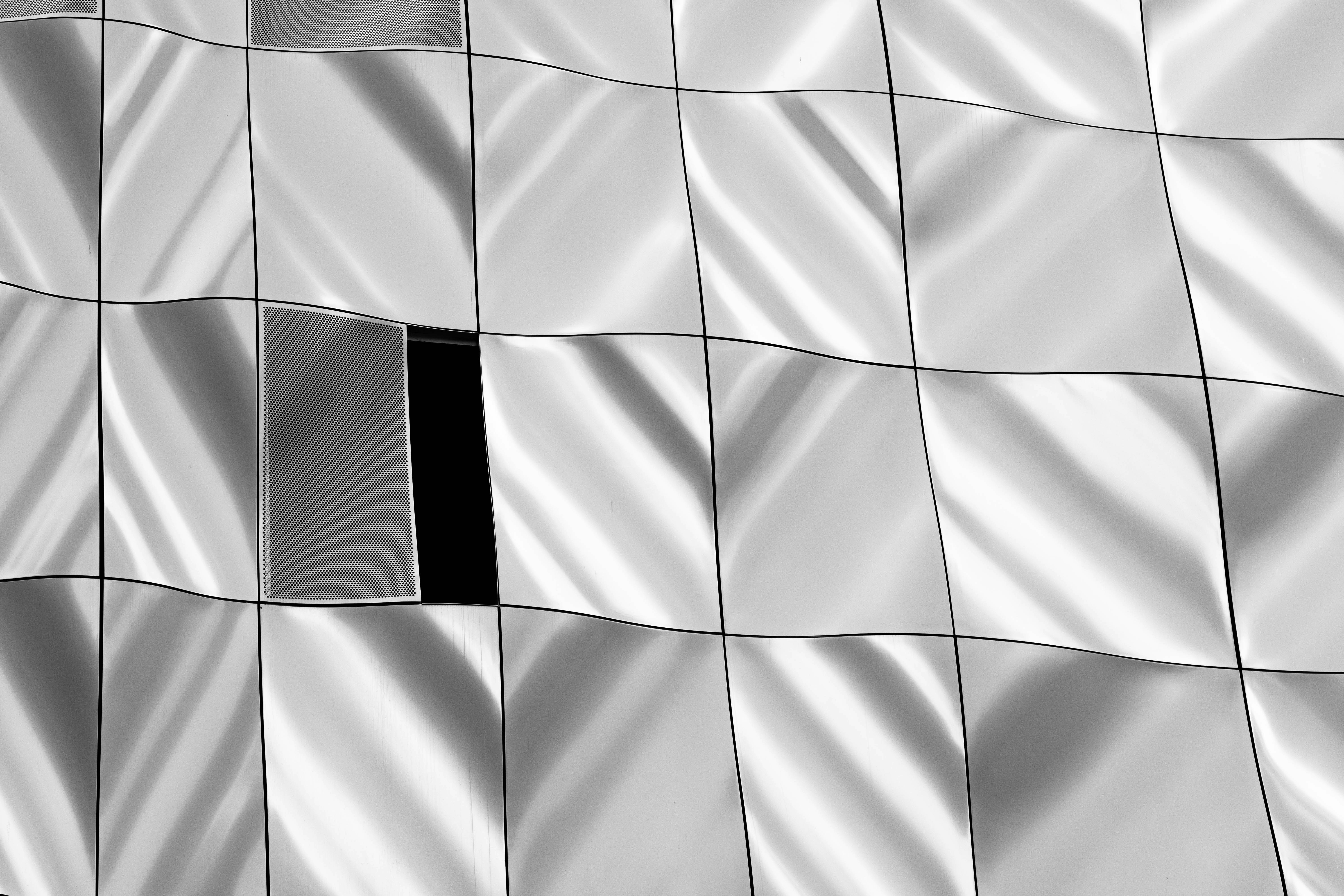 Abstract composition of a reflective surface with a contrasting black void amidst the shimmering panels.