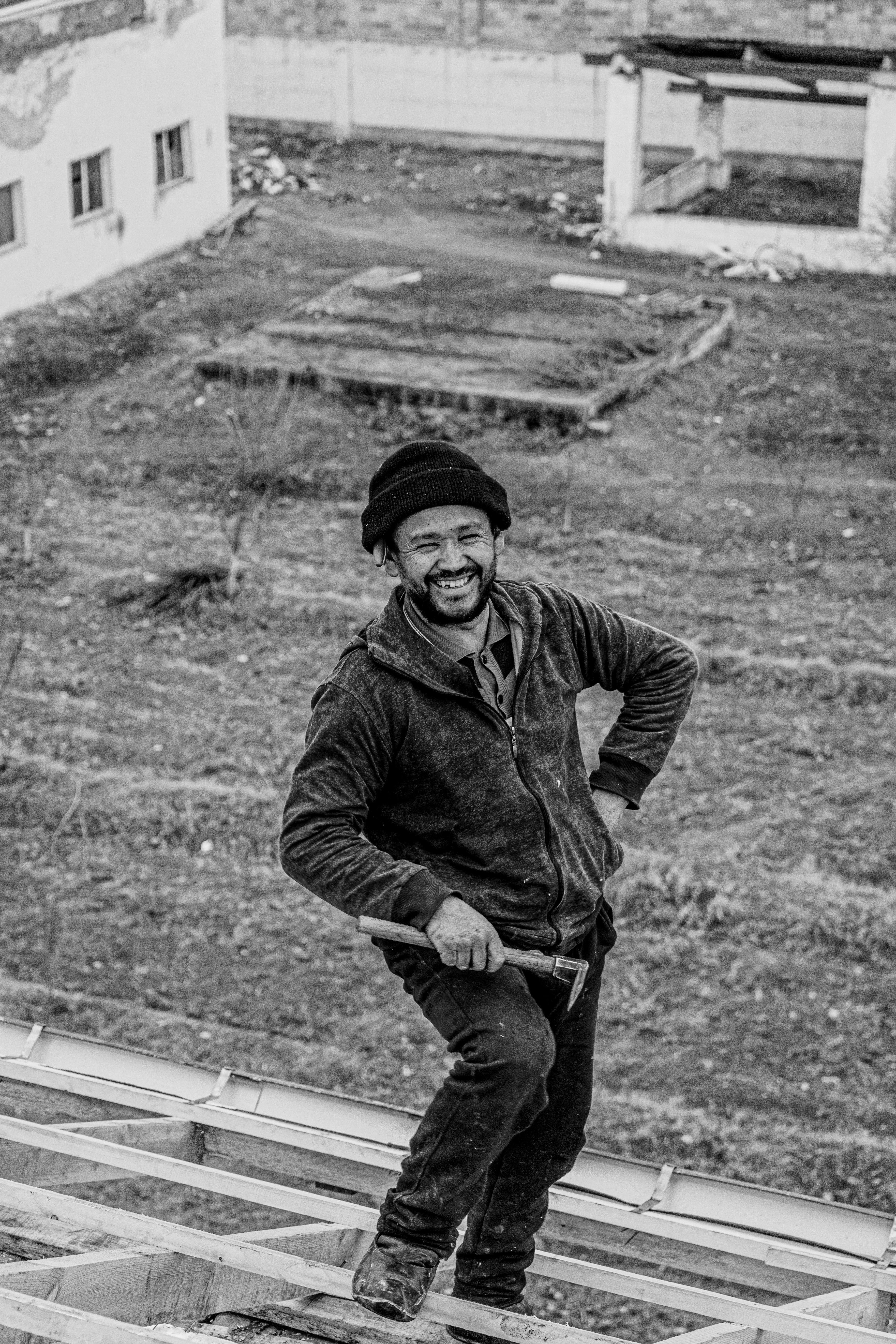 Man with a Hammer on a Construction Deck Smiles Amid Rough Terrain