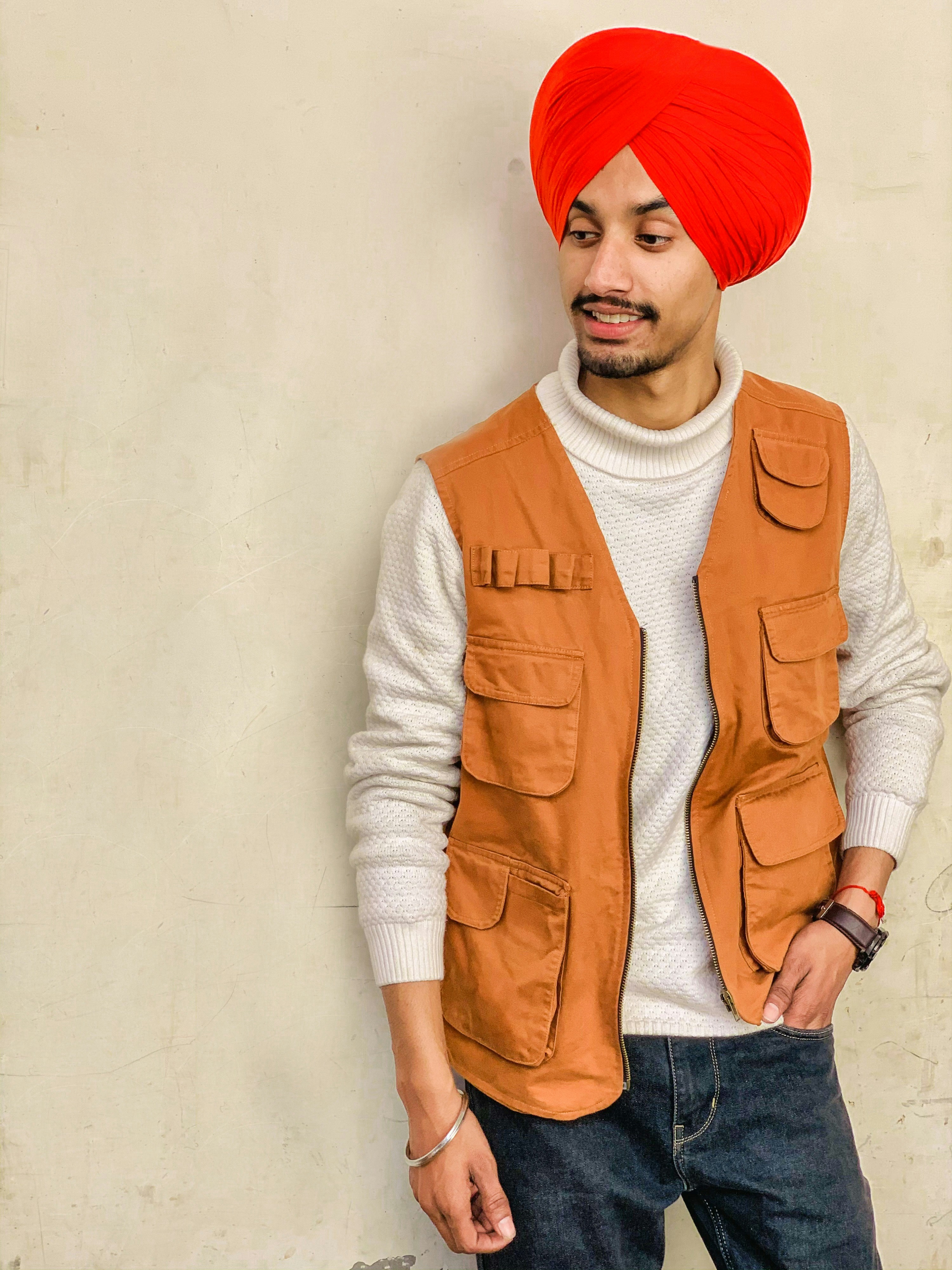 Foto Un hombre con un turbante rojo parado junto a una pared – Imagen ...